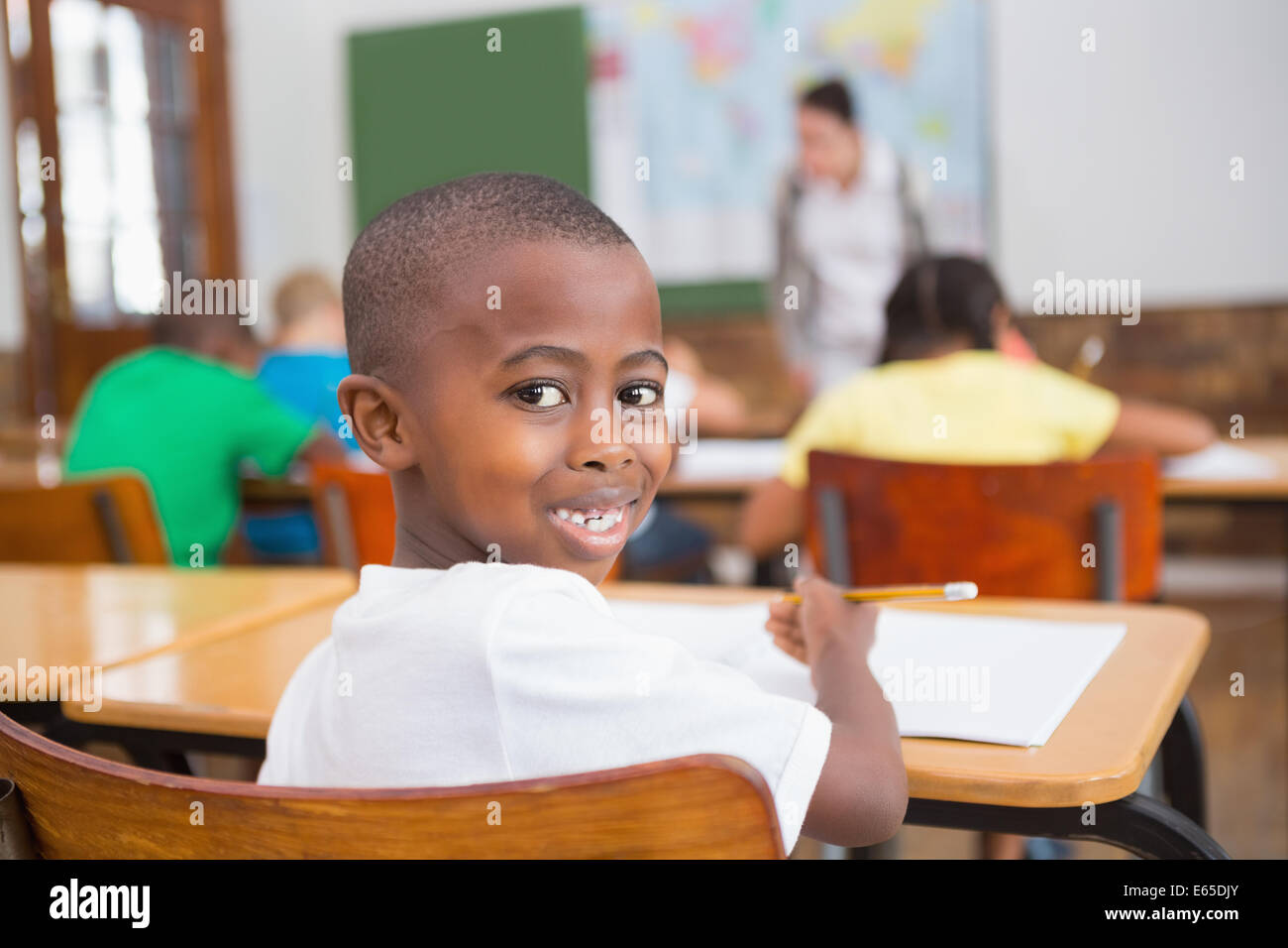 Cute pupil smiling at camera at his desk in classroom Stock Photo - Alamy