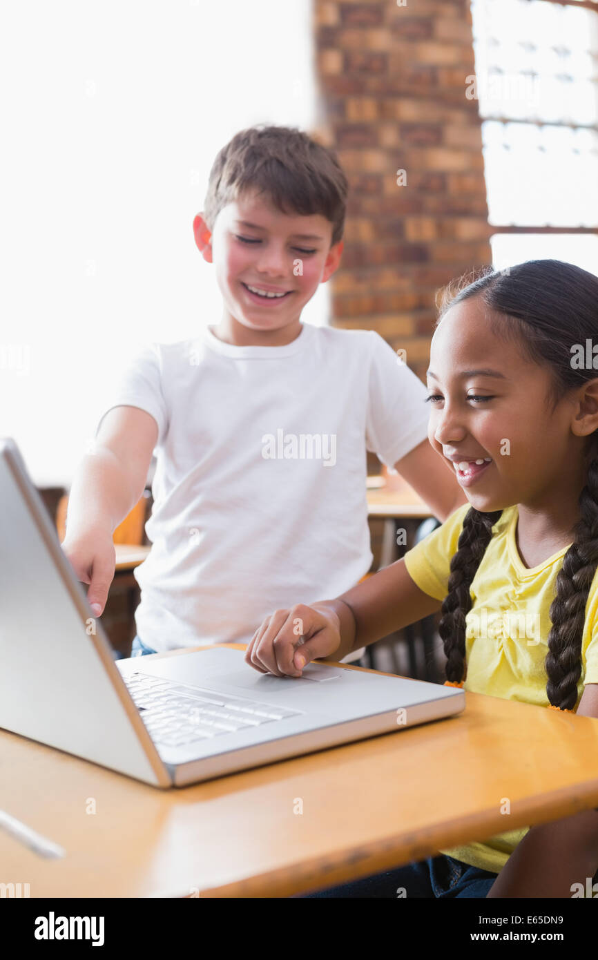 Cute little pupils looking at laptop in classroom Stock Photo - Alamy