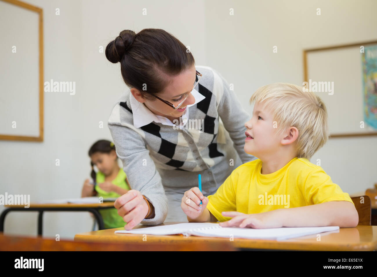 Pretty teacher helping pupil in classroom Stock Photo - Alamy