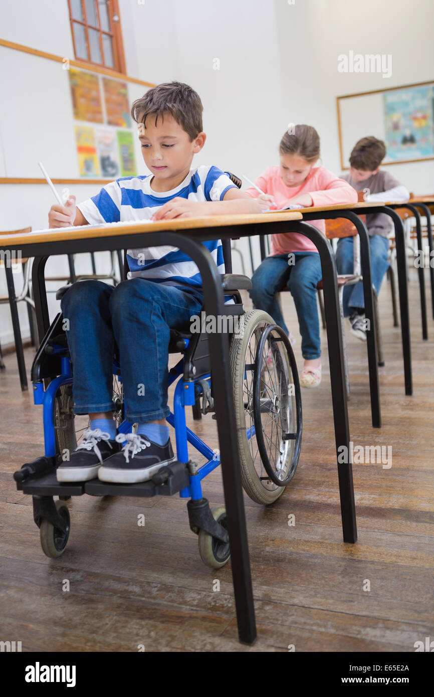 Disabled pupil writing at desk in classroom Stock Photo - Alamy
