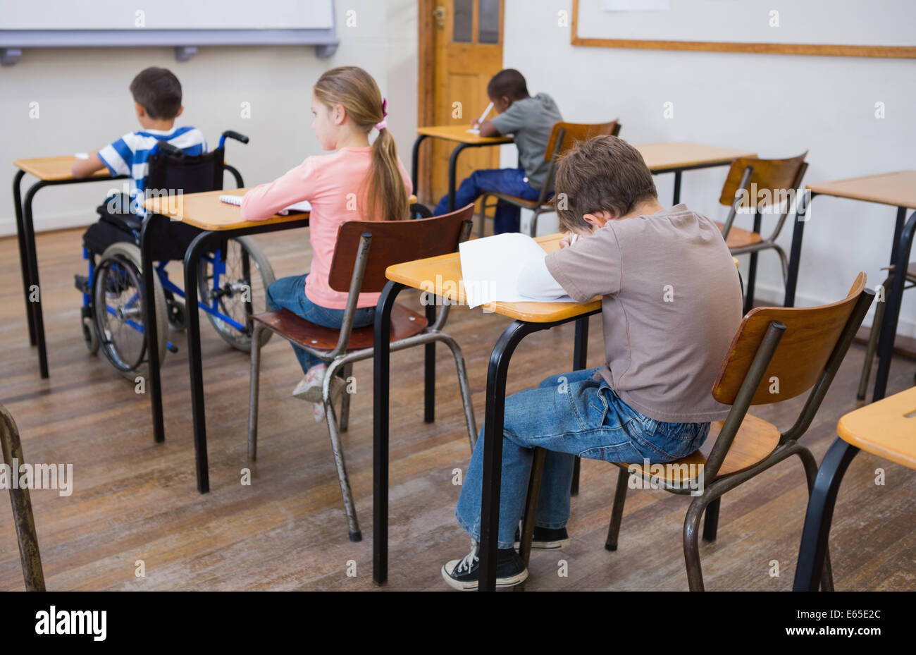 Disabled pupil writing at desk in classroom Stock Photo - Alamy