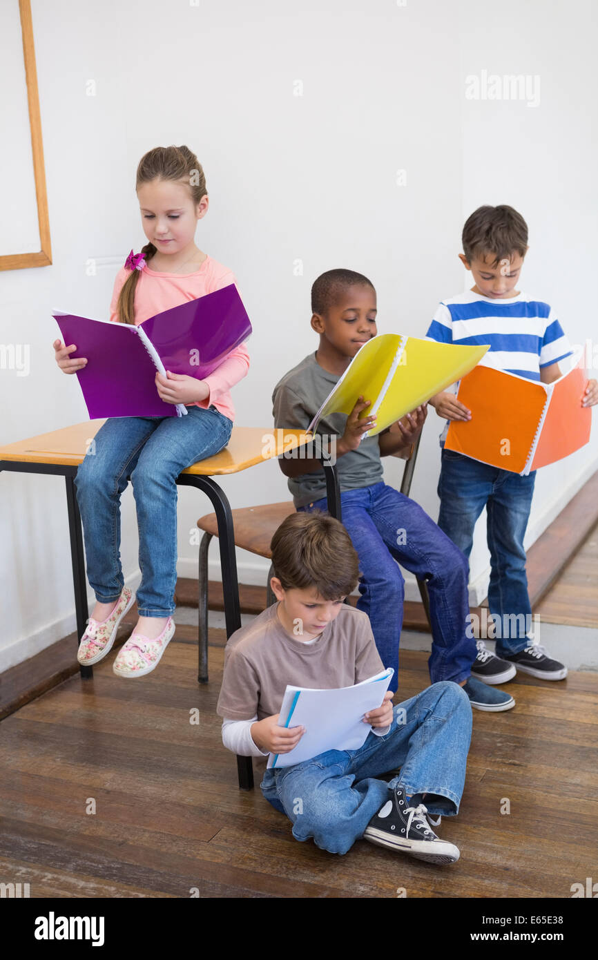 Classmates reading from notepads in classroom Stock Photo - Alamy