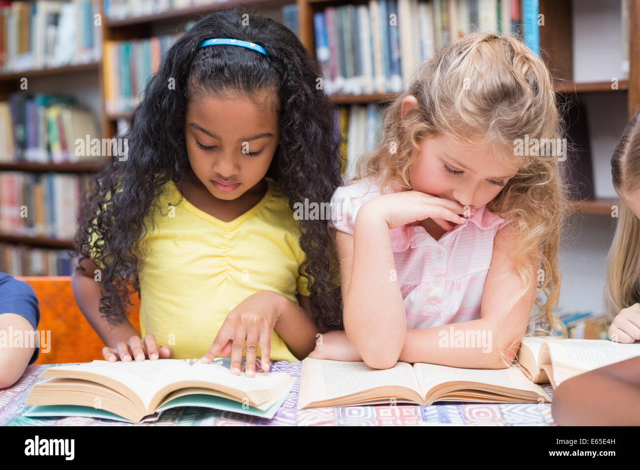 Cute pupils reading books in library Stock Photo - Alamy