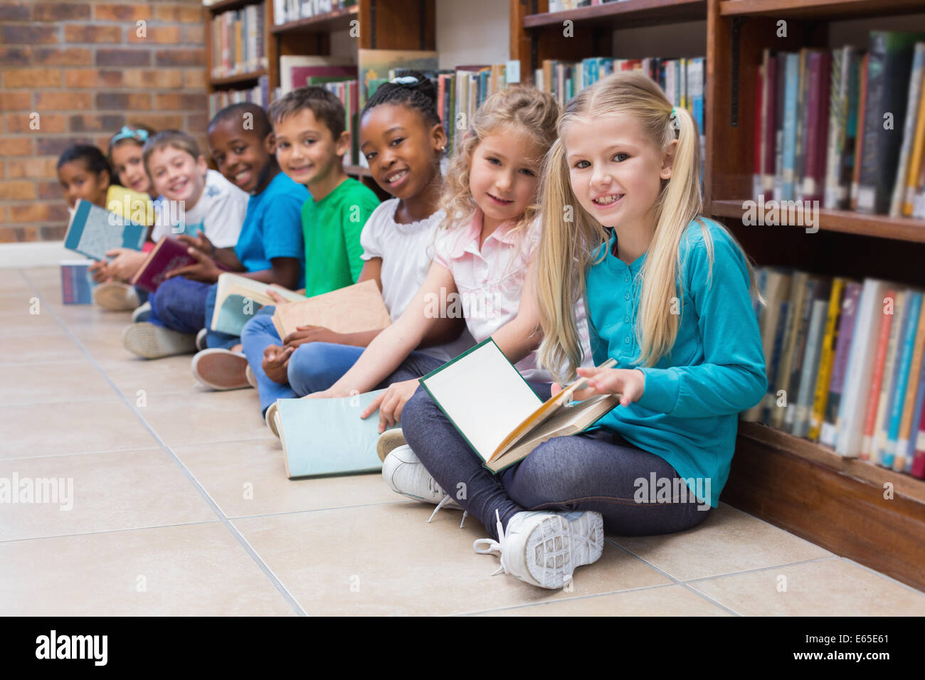 Cute pupils sitting on floor in library Stock Photo - Alamy