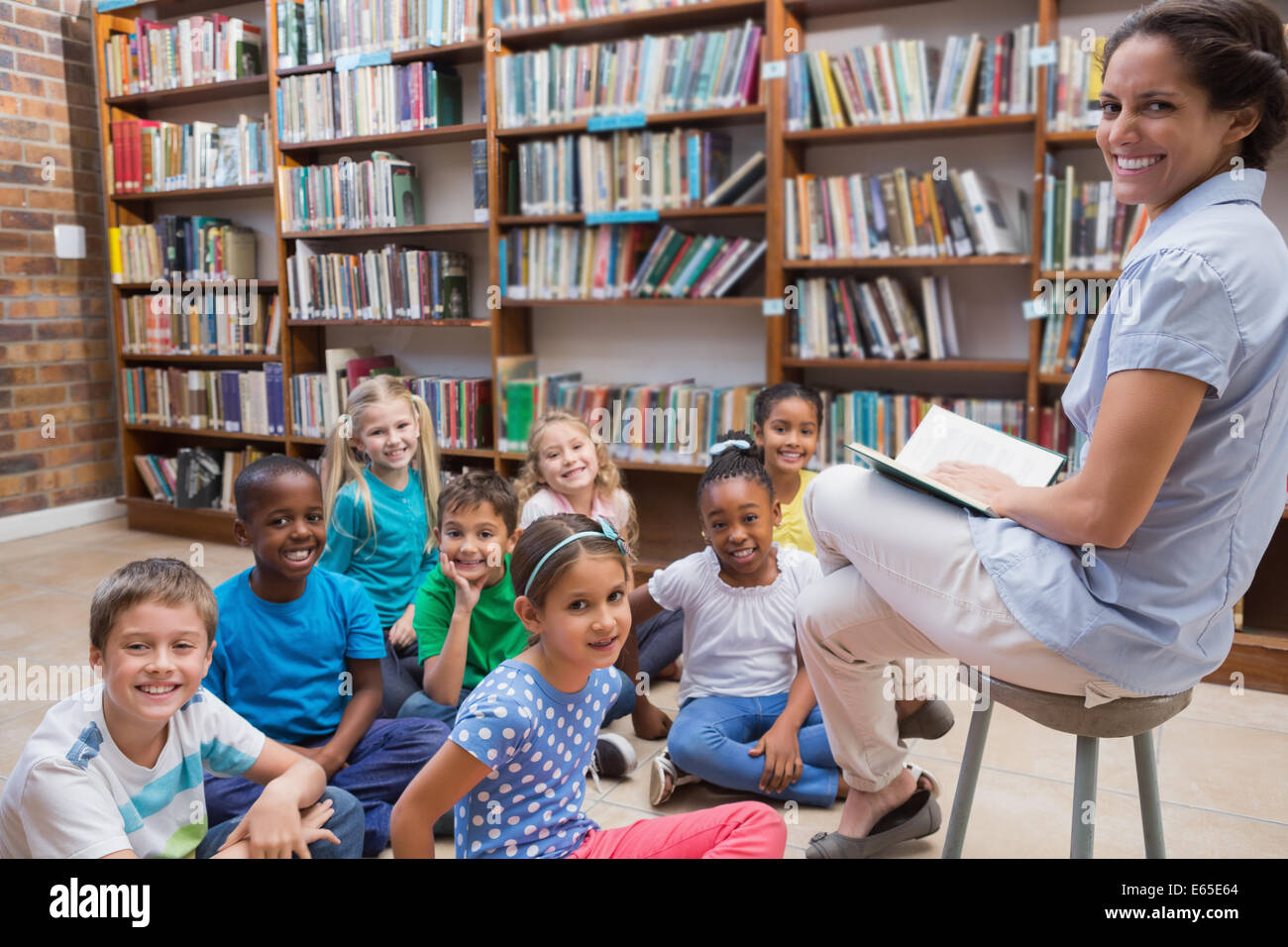 Cute pupils sitting on floor in library Stock Photo - Alamy