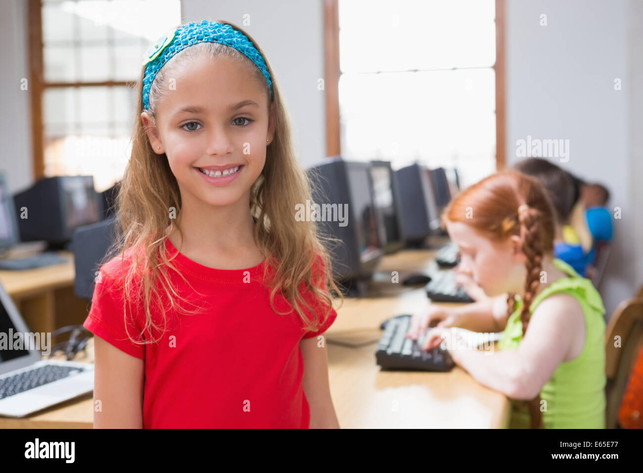Cute pupil in computer class smiling at camera Stock Photo - Alamy