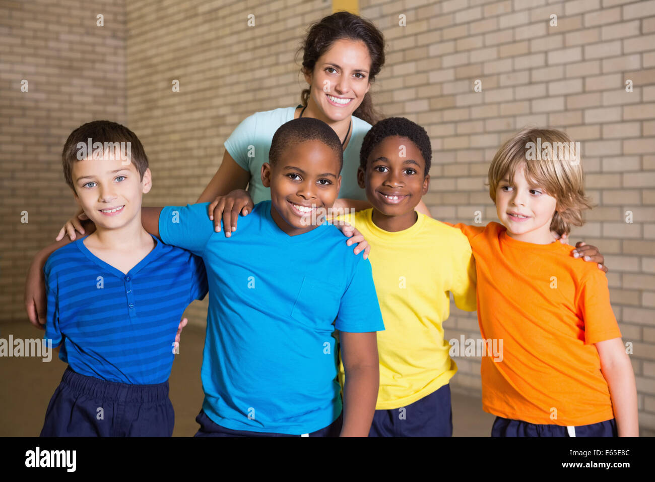 Cute pupils smiling at camera with PE teacher Stock Photo - Alamy