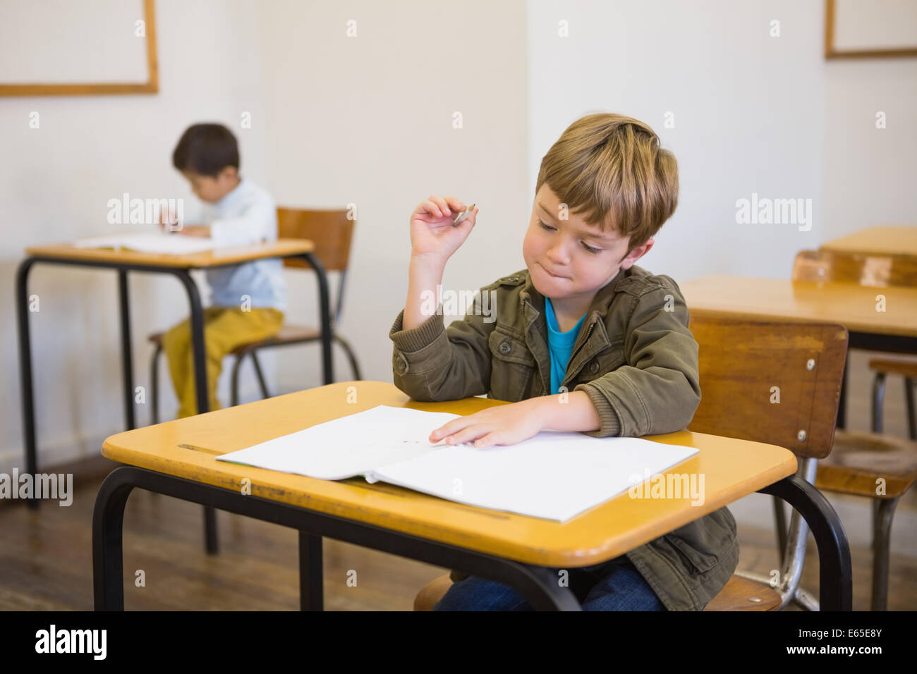 Pupil writing in notepad at his desk Stock Photo - Alamy