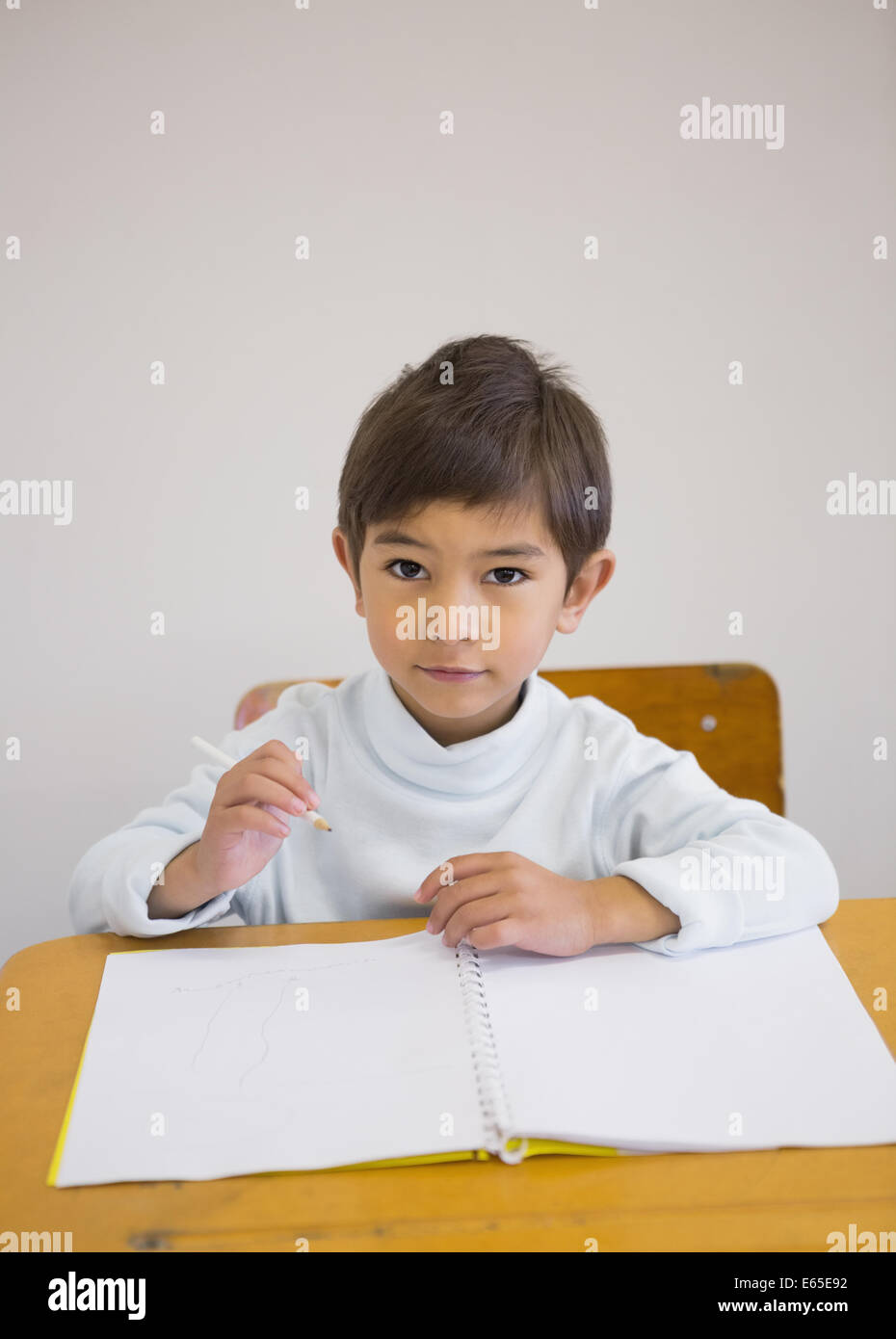 Pupil writing in notepad at his desk smiling at camera Stock Photo - Alamy