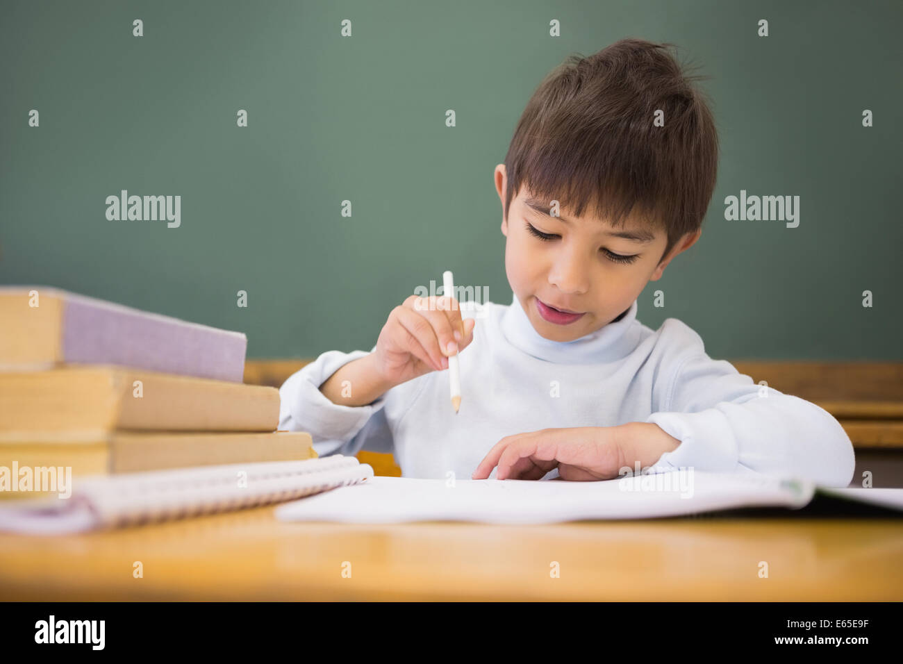 Happy pupil writing in notepad at desk Stock Photo - Alamy