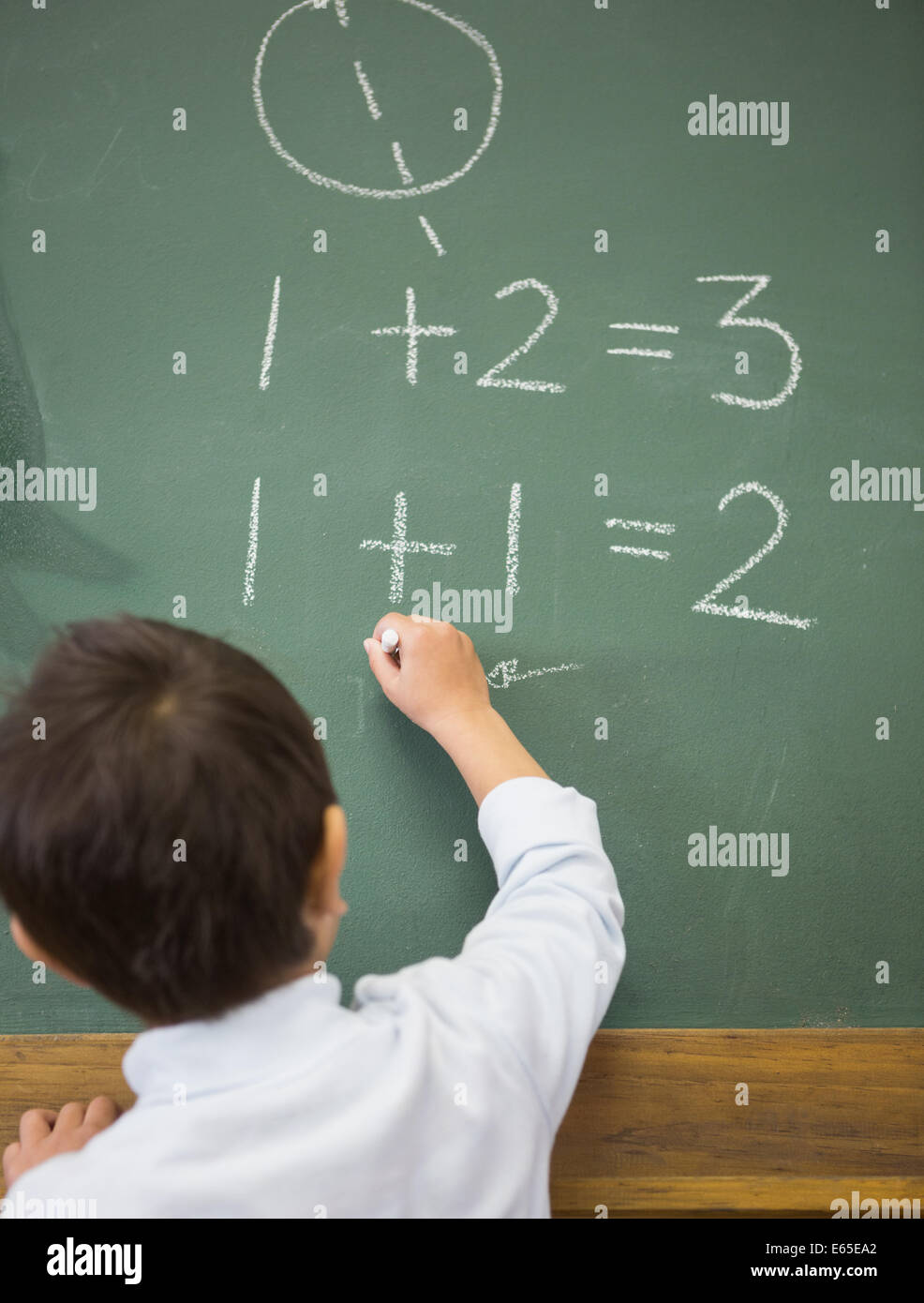 Cute pupil writing maths on chalkboard Stock Photo - Alamy