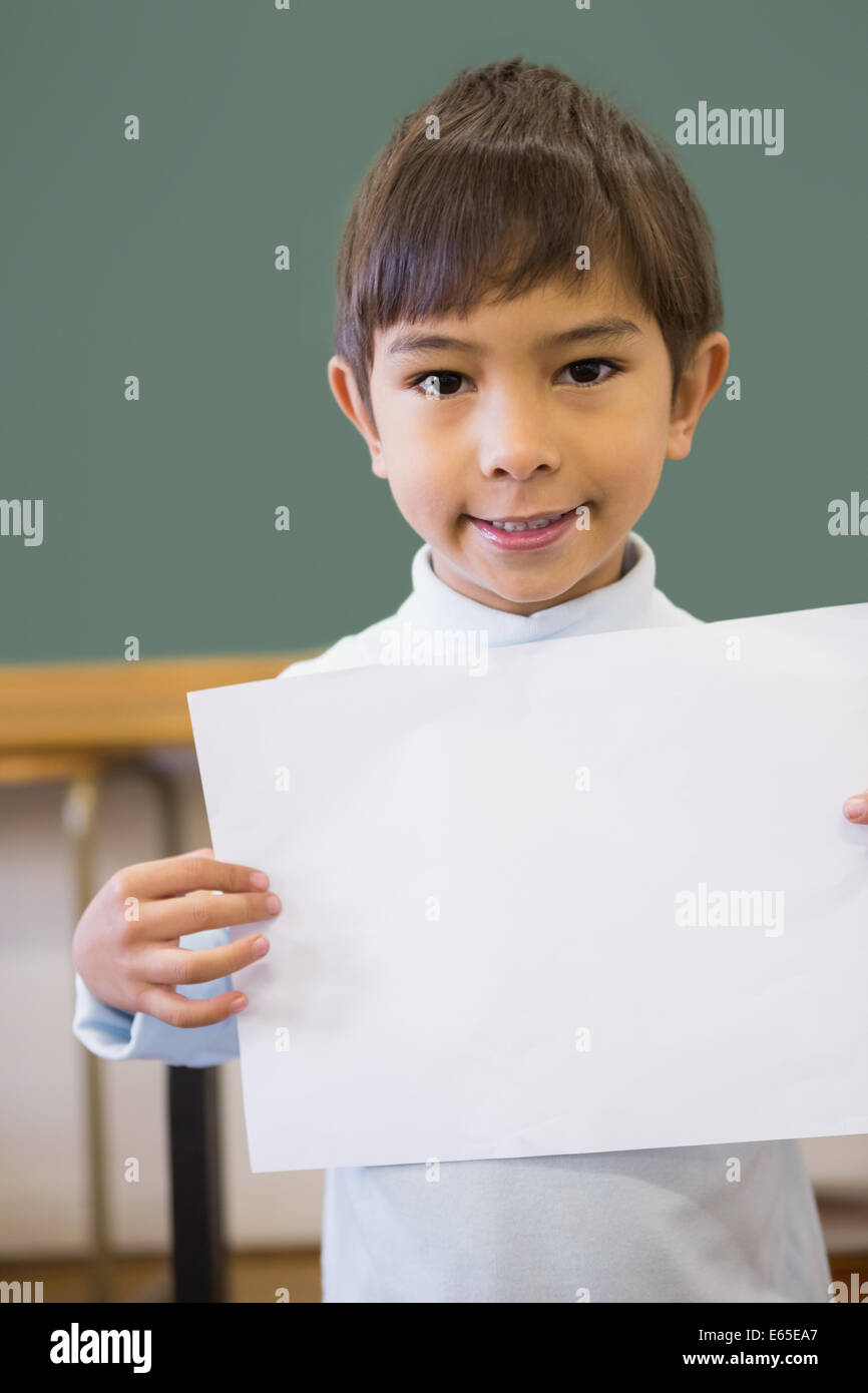 Cute pupil smiling at camera in classroom showing page Stock Photo - Alamy