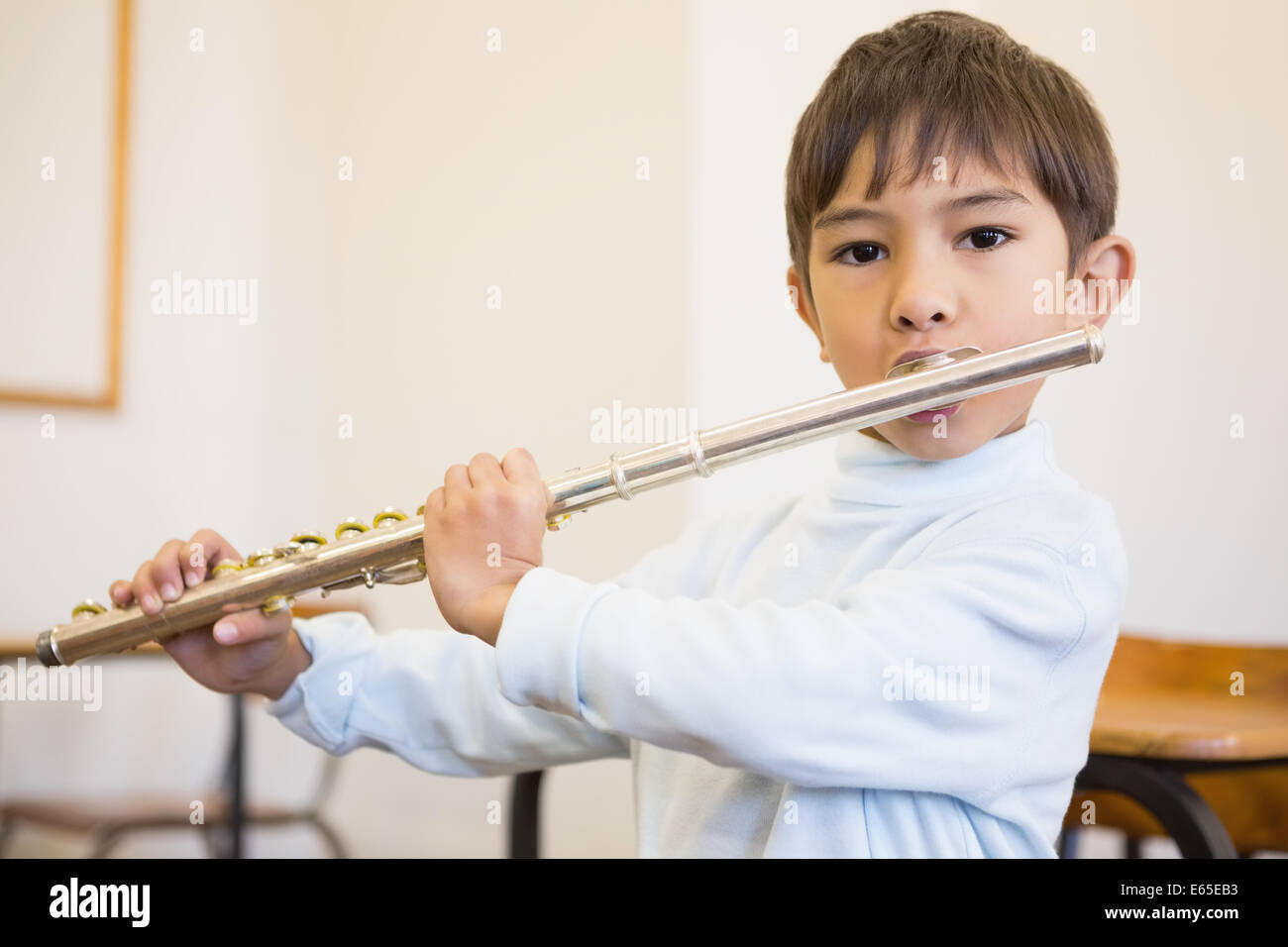 Cute pupil playing flute in classroom Stock Photo - Alamy