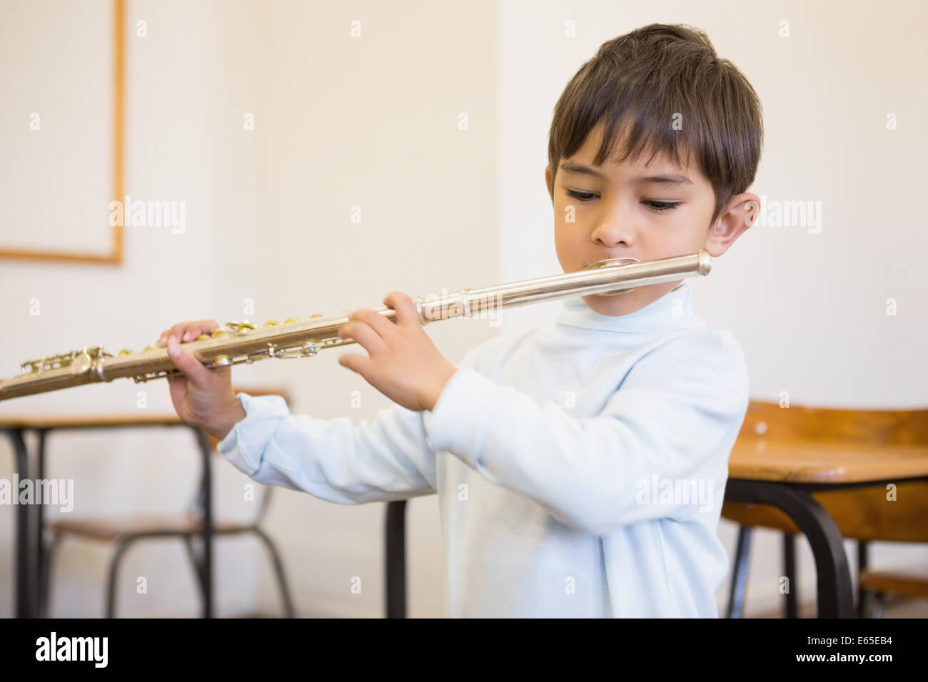 Cute pupil playing flute in classroom Stock Photo - Alamy
