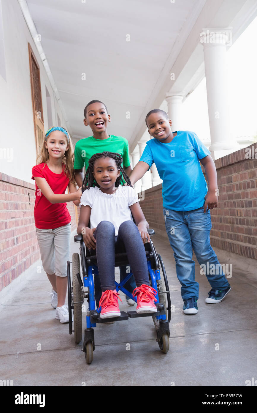 Cute disabled pupil smiling at camera in hall with her friends Stock ...