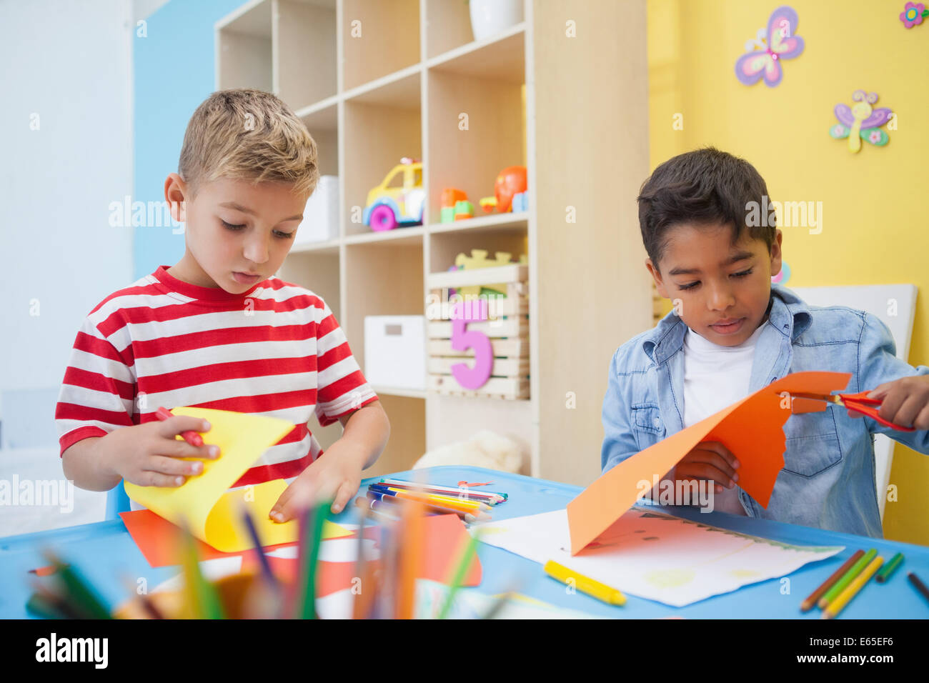 Cute little boys cutting paper shapes in classroom Stock Photo - Alamy