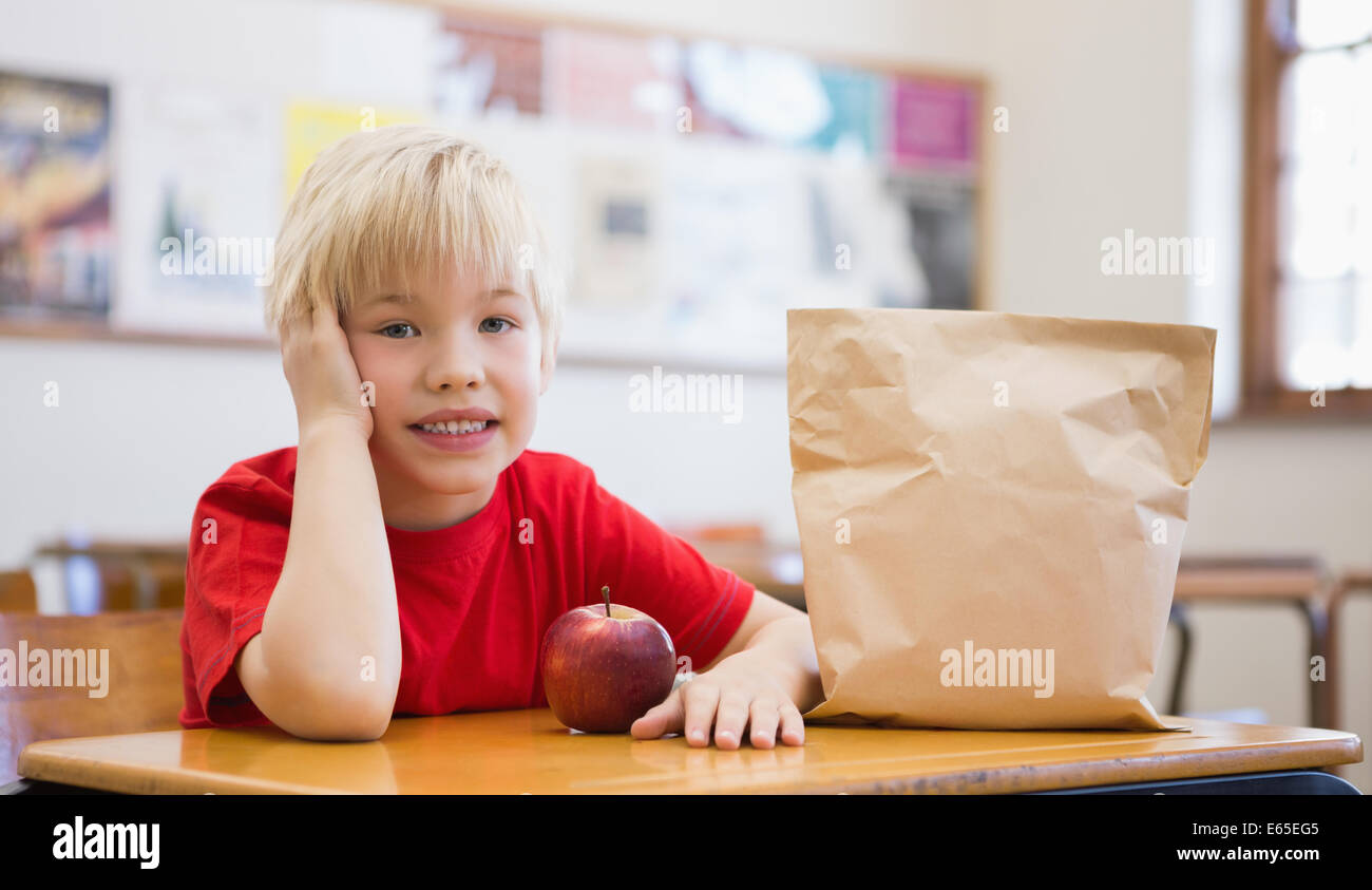 Cute pupil smiling at camera at desk in classroom Stock Photo - Alamy