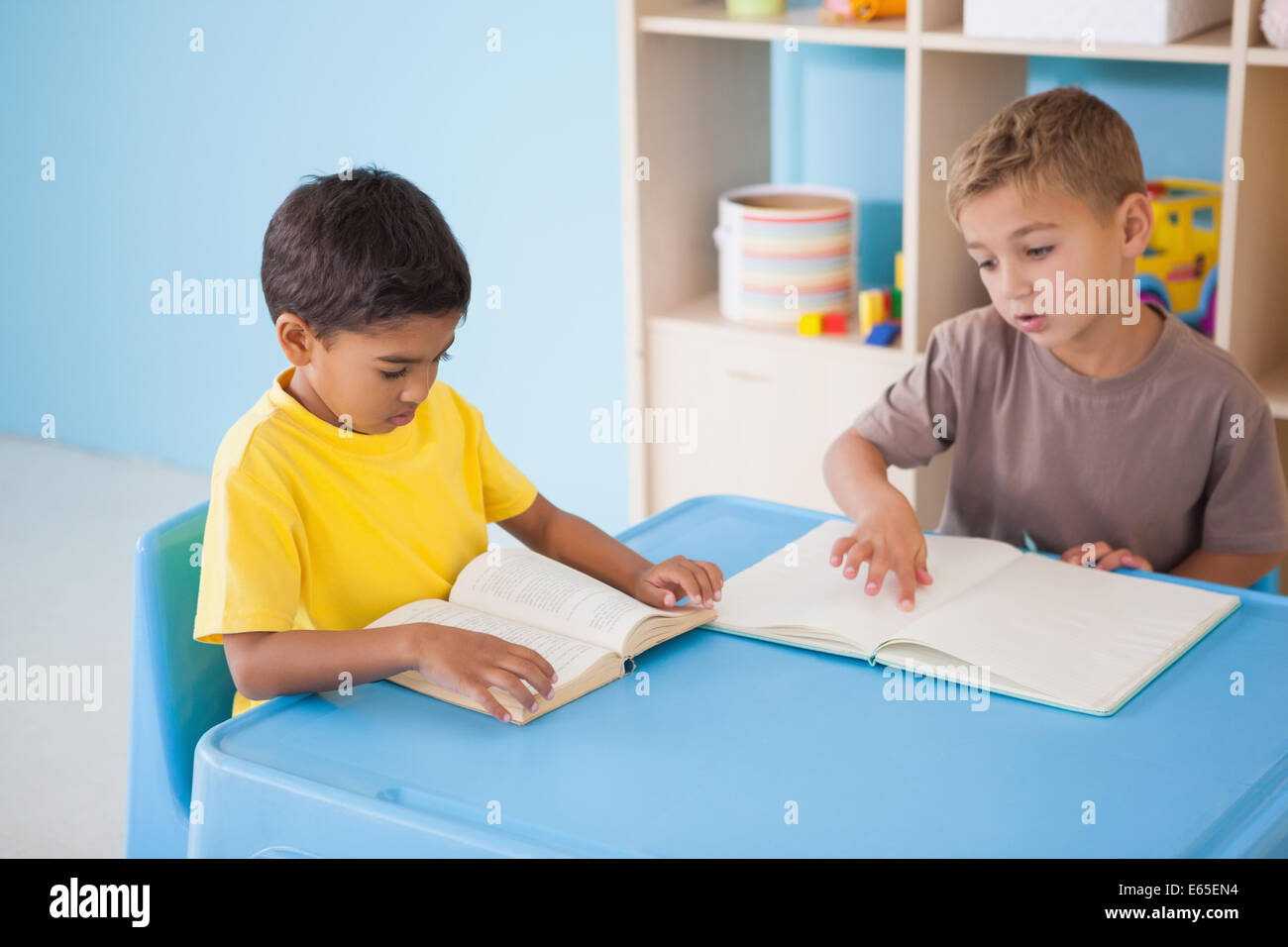 Cute little boys reading at desk in classroom Stock Photo - Alamy