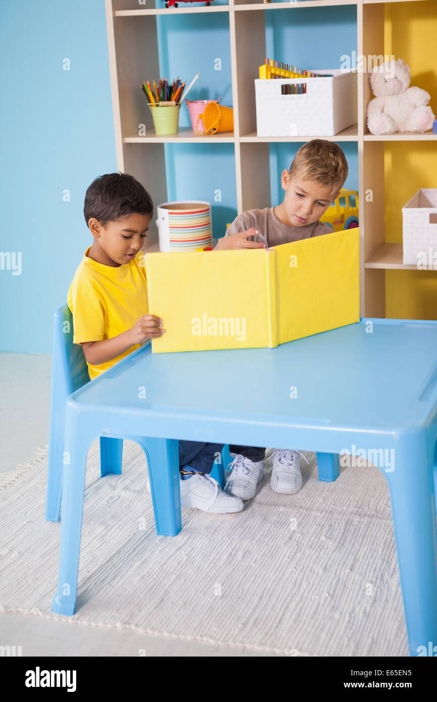 Cute little boys reading at desk in classroom Stock Photo - Alamy