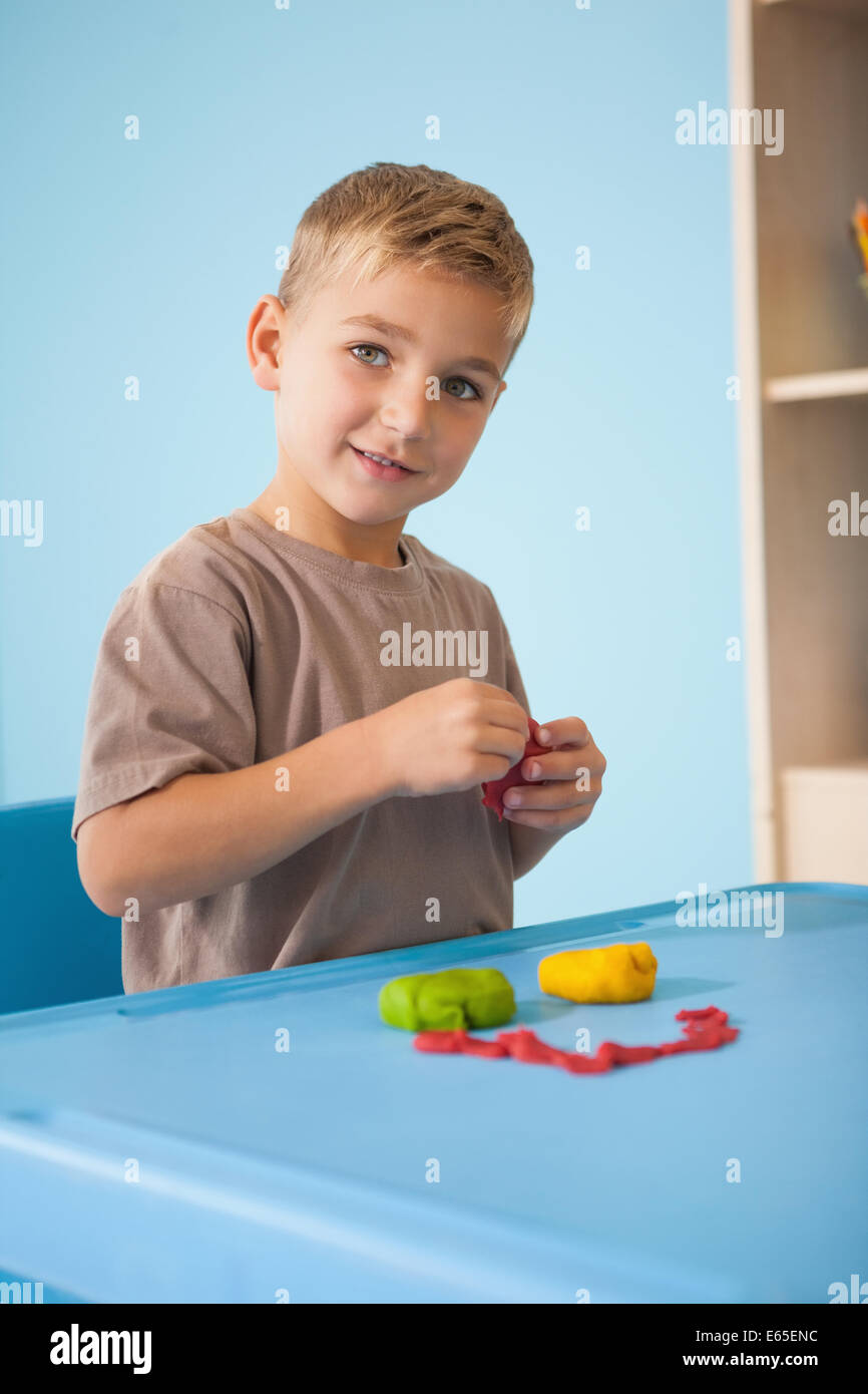 Cute little boy playing with modelling clay in classroom Stock Photo ...