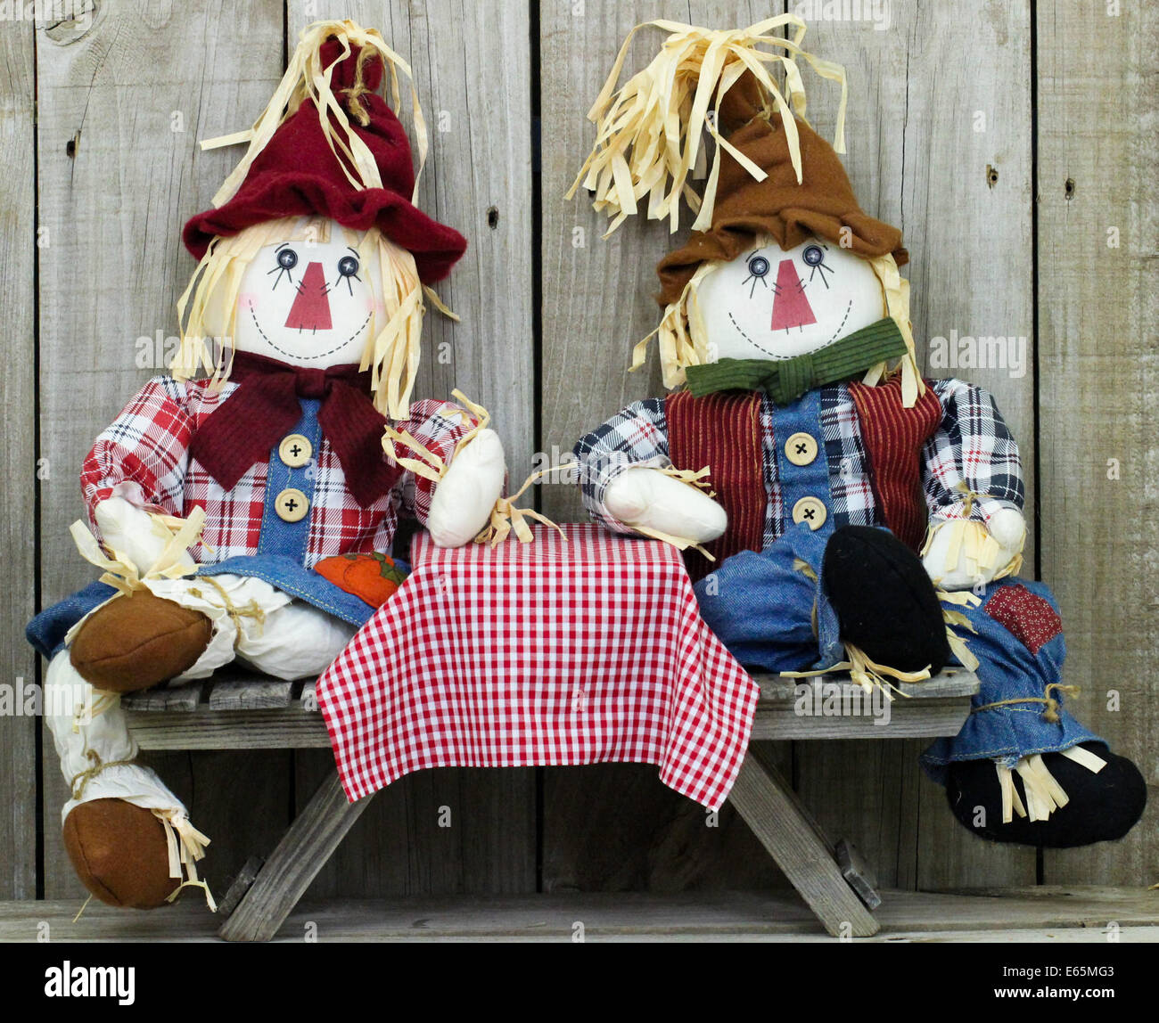 Boy and girl scarecrows sitting on picnic table with red checkered ...