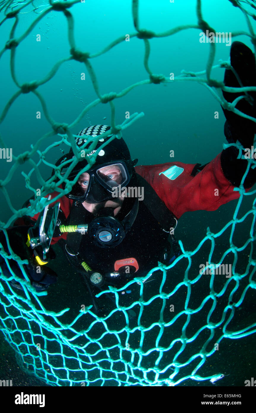 Diver cutting away netting Stock Photo - Alamy
