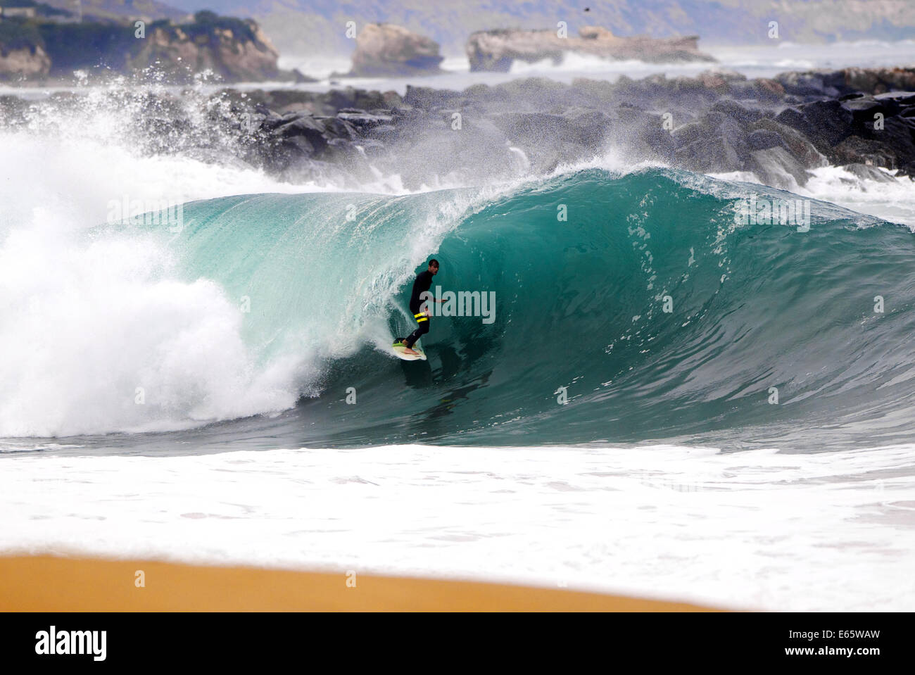 A local surfer pulls into a heavy, shore breaking barrel in shallow ...
