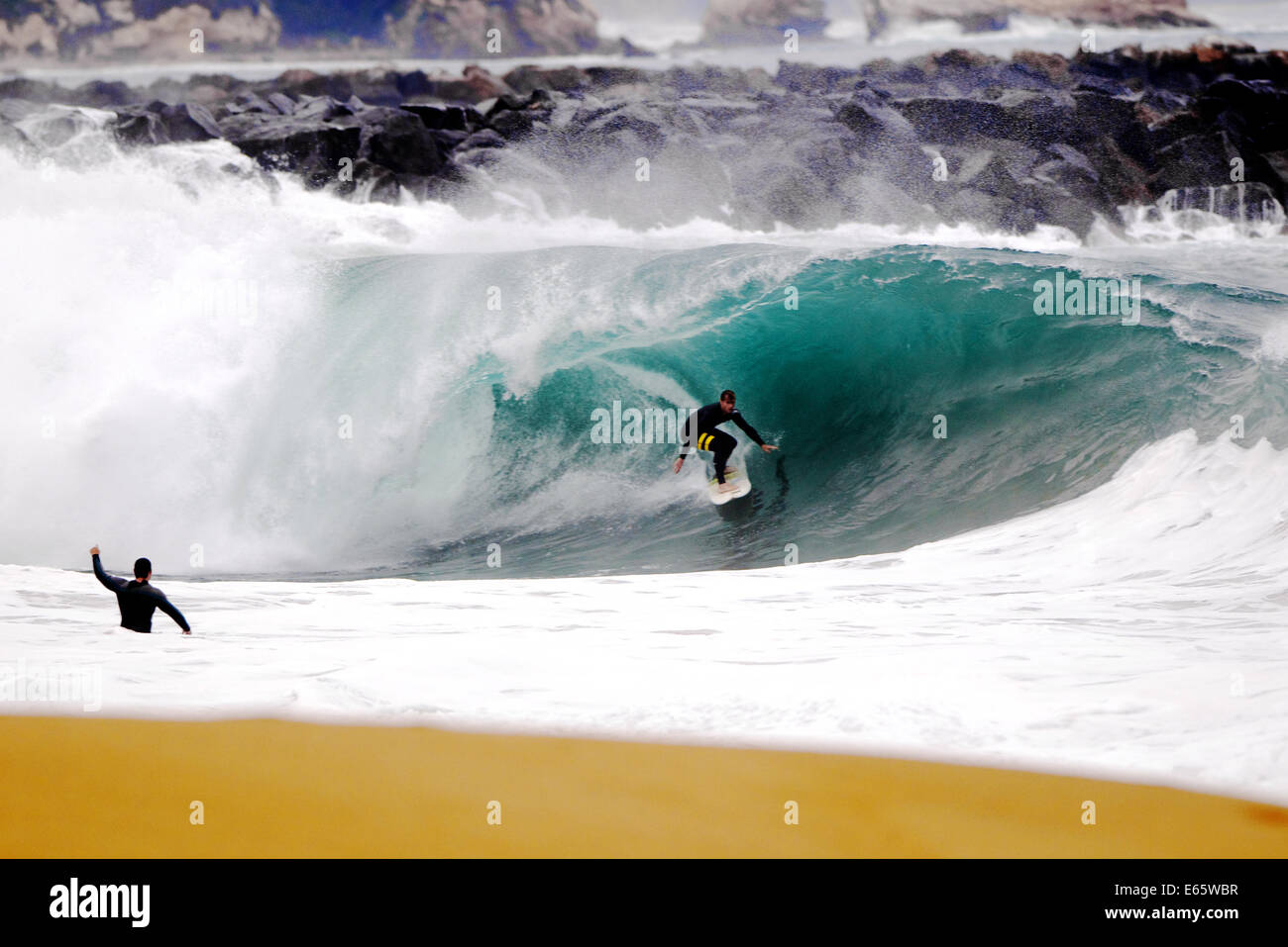 A local surfer pulls into a heavy, shore breaking barrel in shallow ...