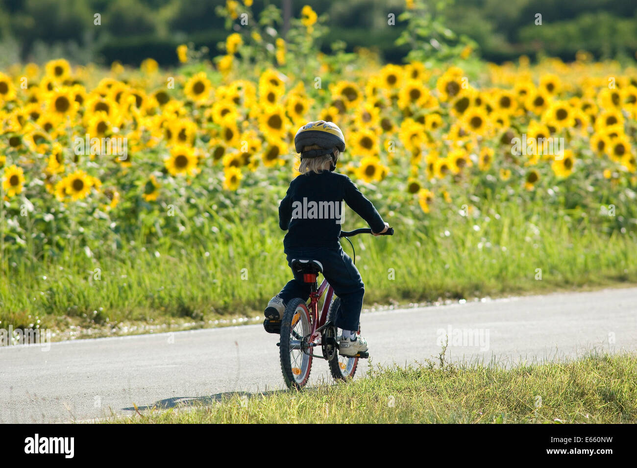Boy rides bike back to camera lens hi-res stock photography and images ...