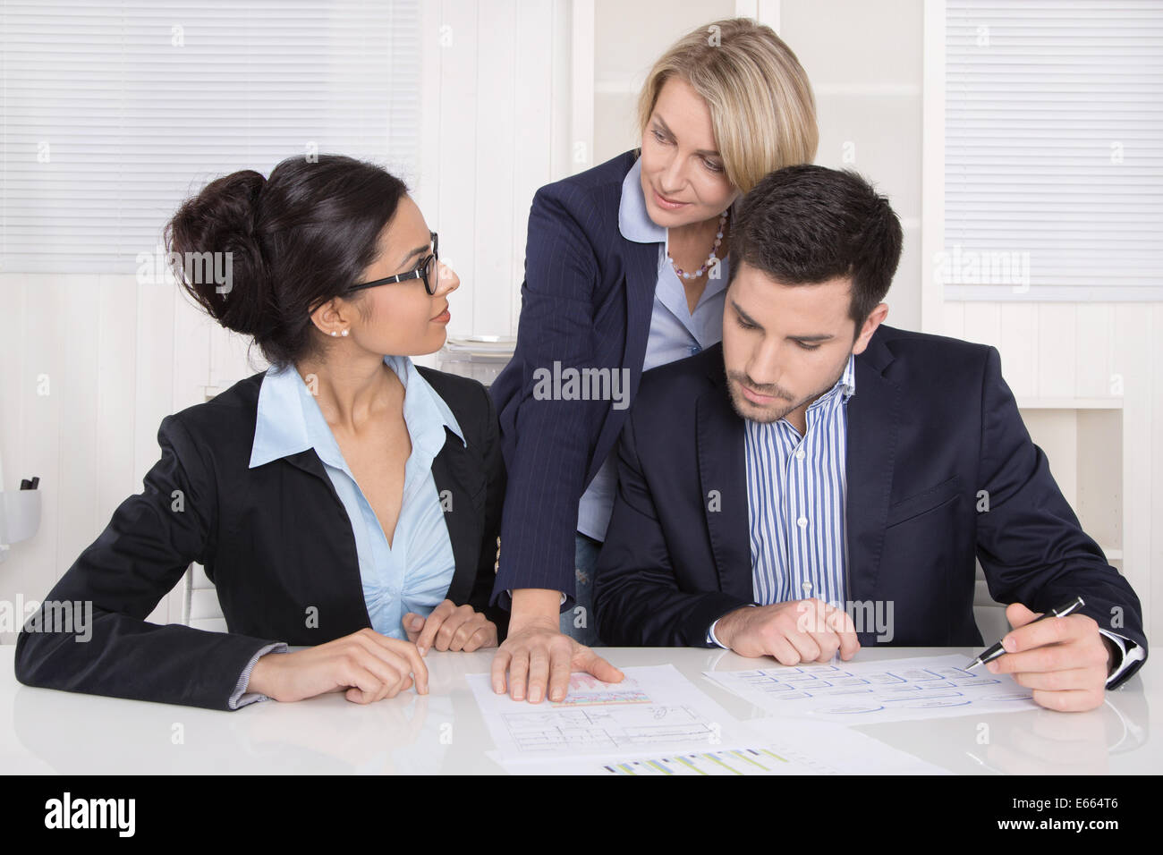 Portrait of a business team sitting around a table in a meeting talking ...