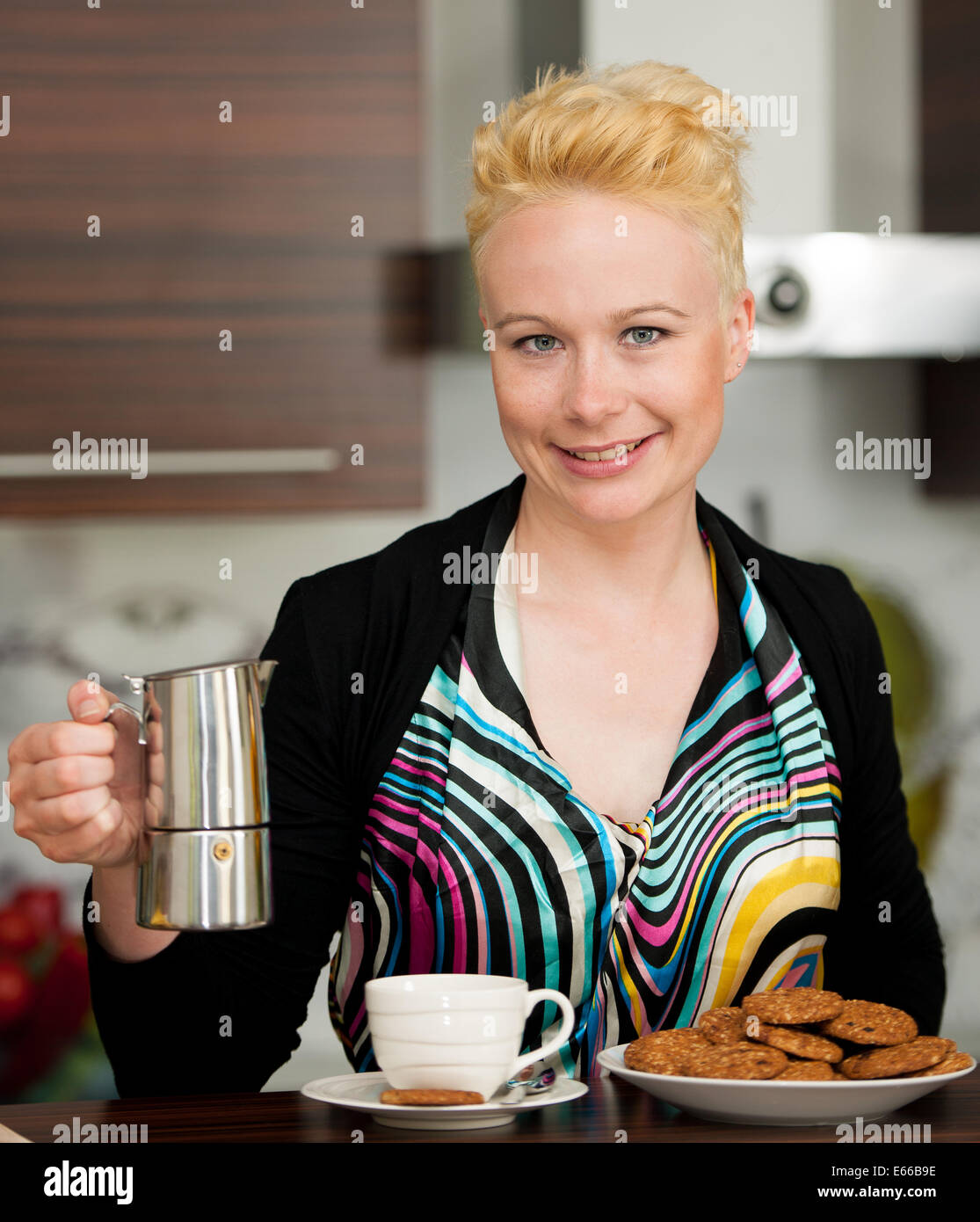 beautiful young caucasian blond woman cooking espresso coffee in cosy ...