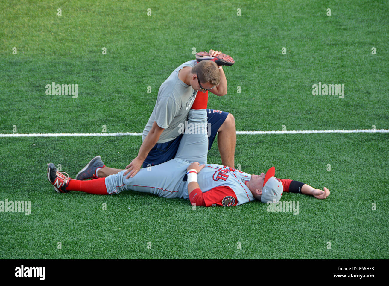 Minor league baseball player stretches before a game with his strength ...
