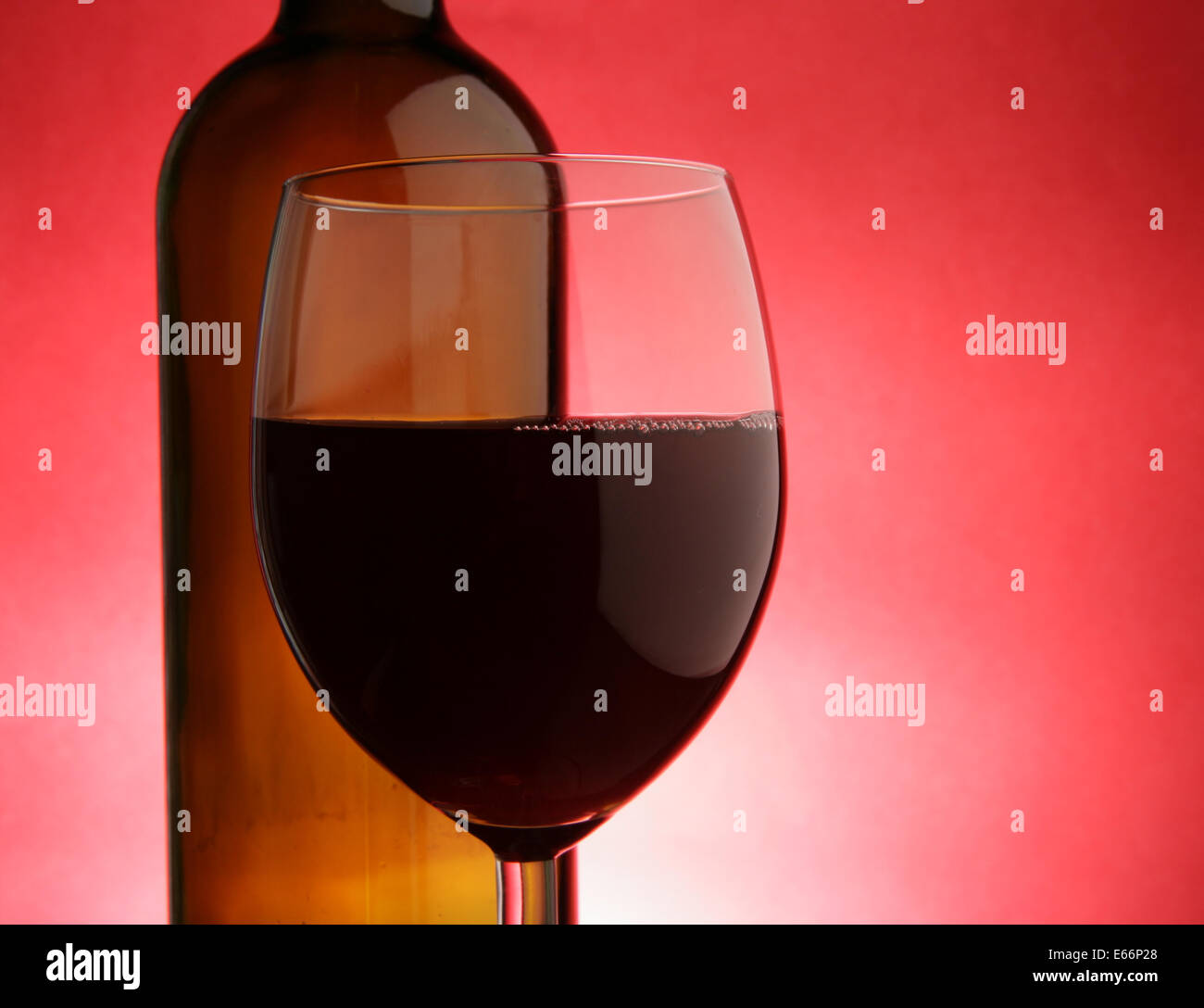 Glass and bottle of red wine over red background Stock Photo - Alamy