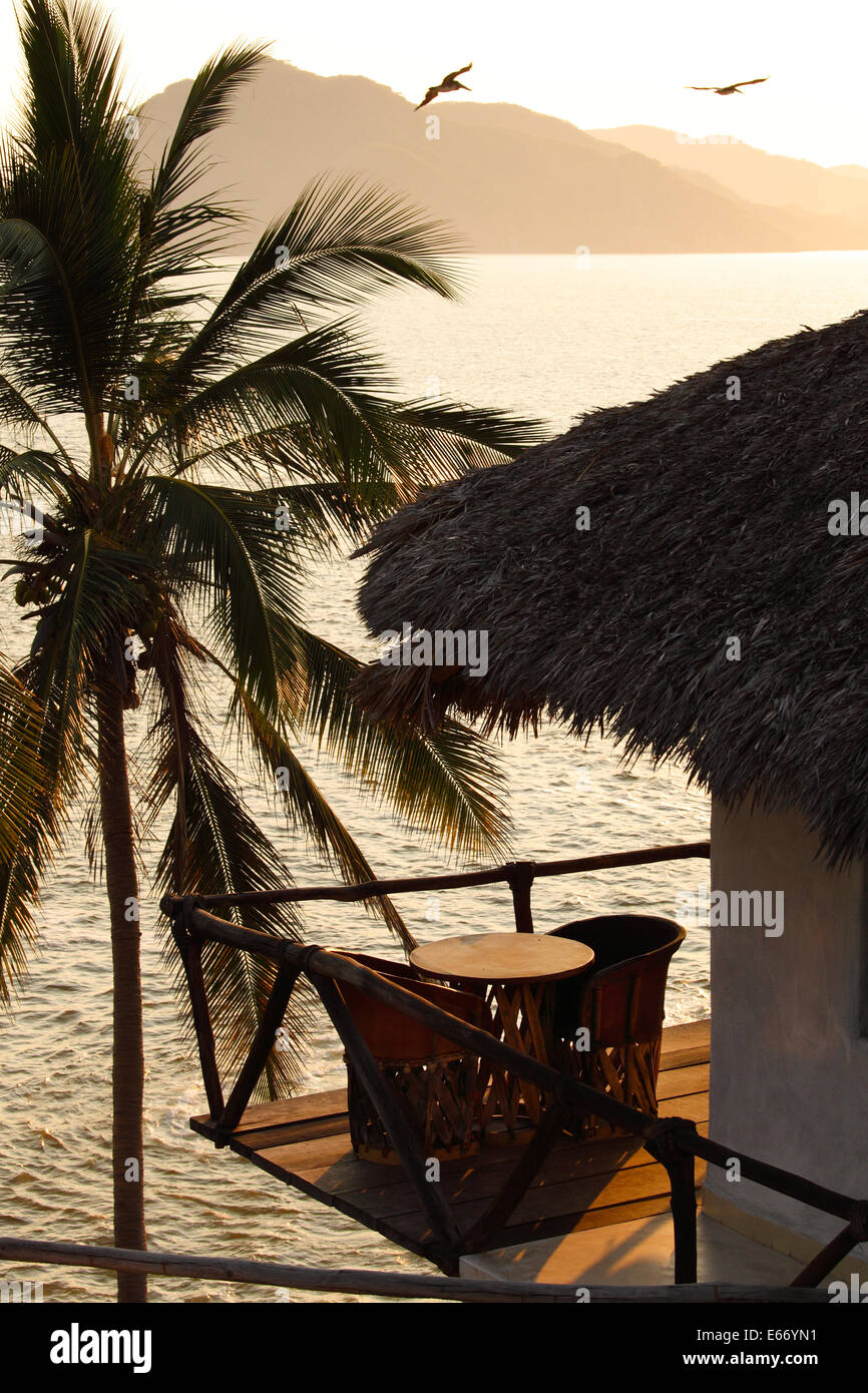 Table and chairs overlook the ocean on a wooden balcony in Manzanillo ...