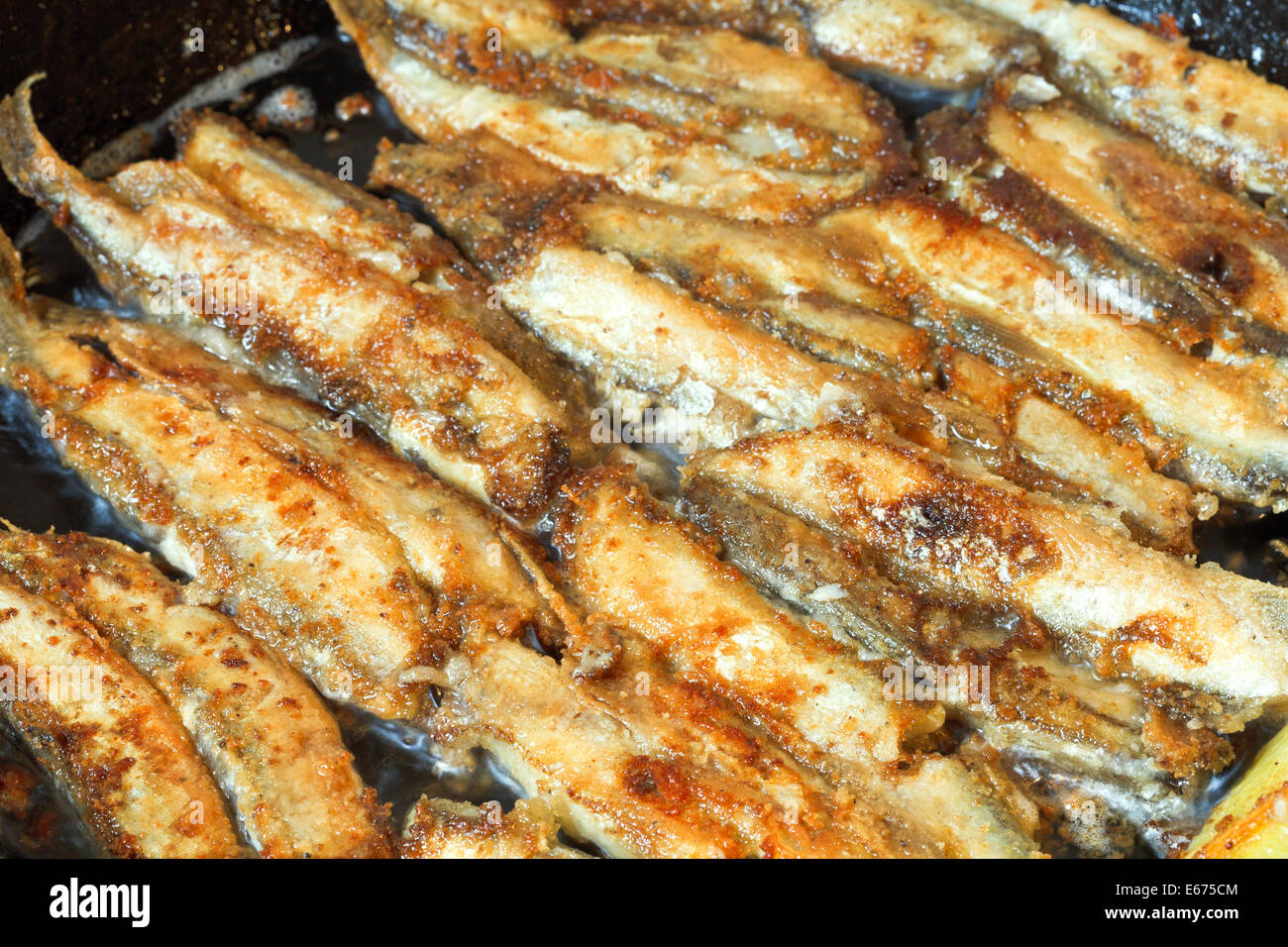 fried fish capelin on black frying pan close up Stock Photo - Alamy