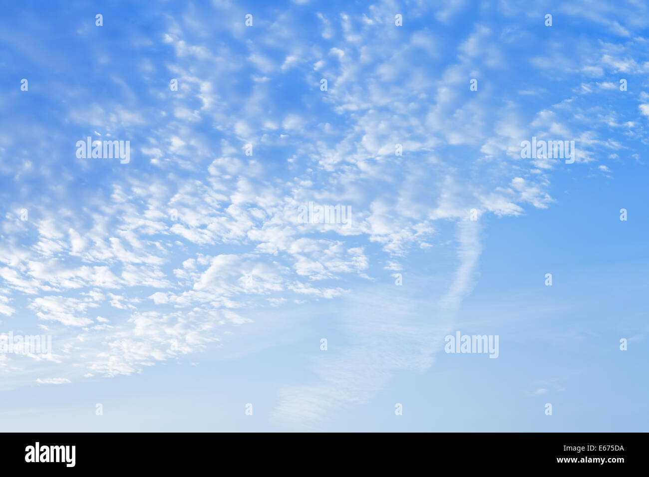 many small puffy white clouds in blue sunrise sky in early morning ...