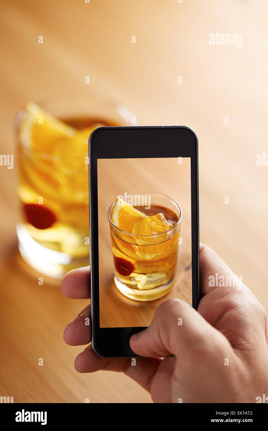 Smartphone taking a picture of old fashioned cocktail Stock Photo - Alamy