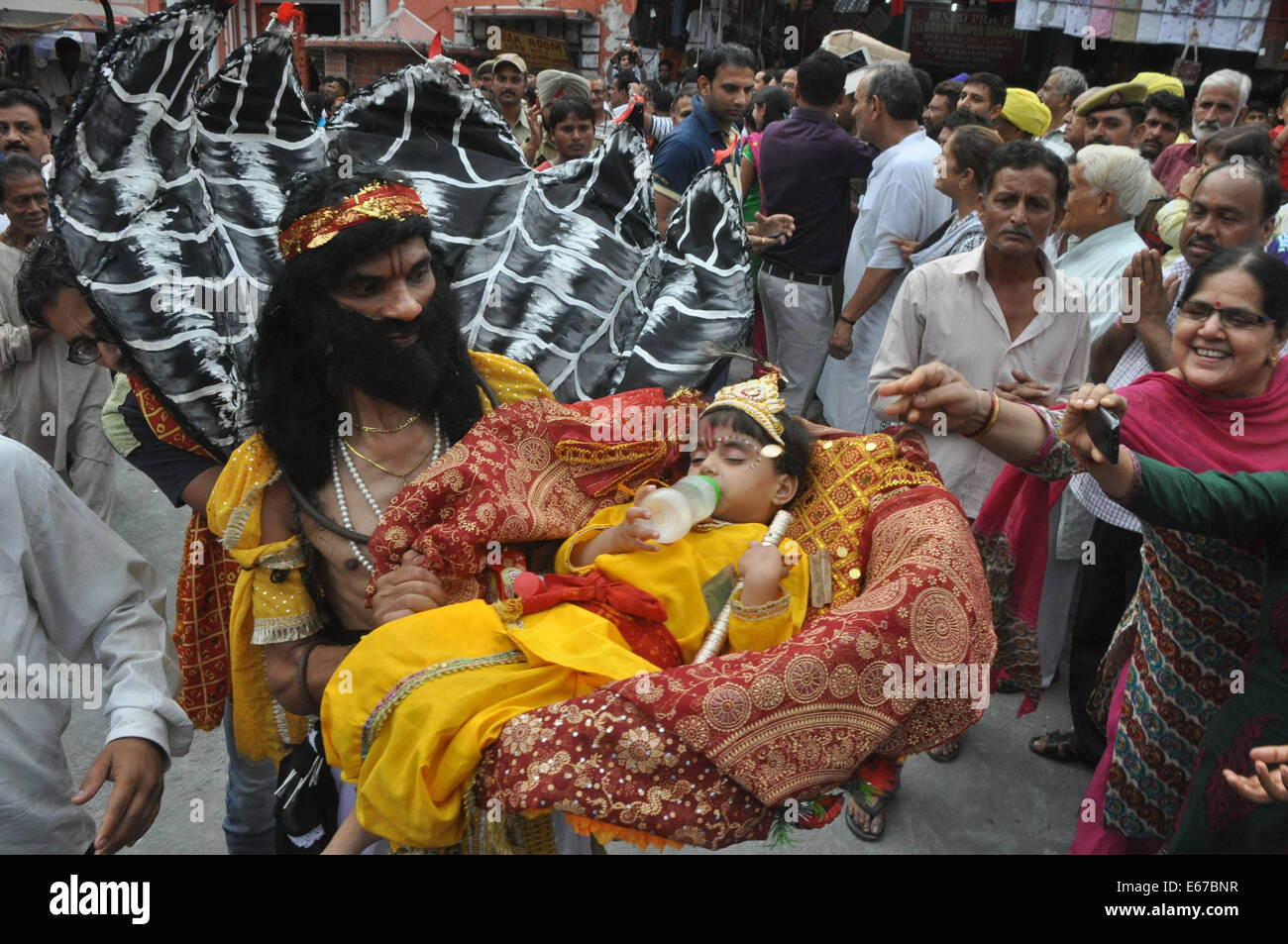 An Indian Hindu devotee carries a child dressed as Lord Krishna during ...