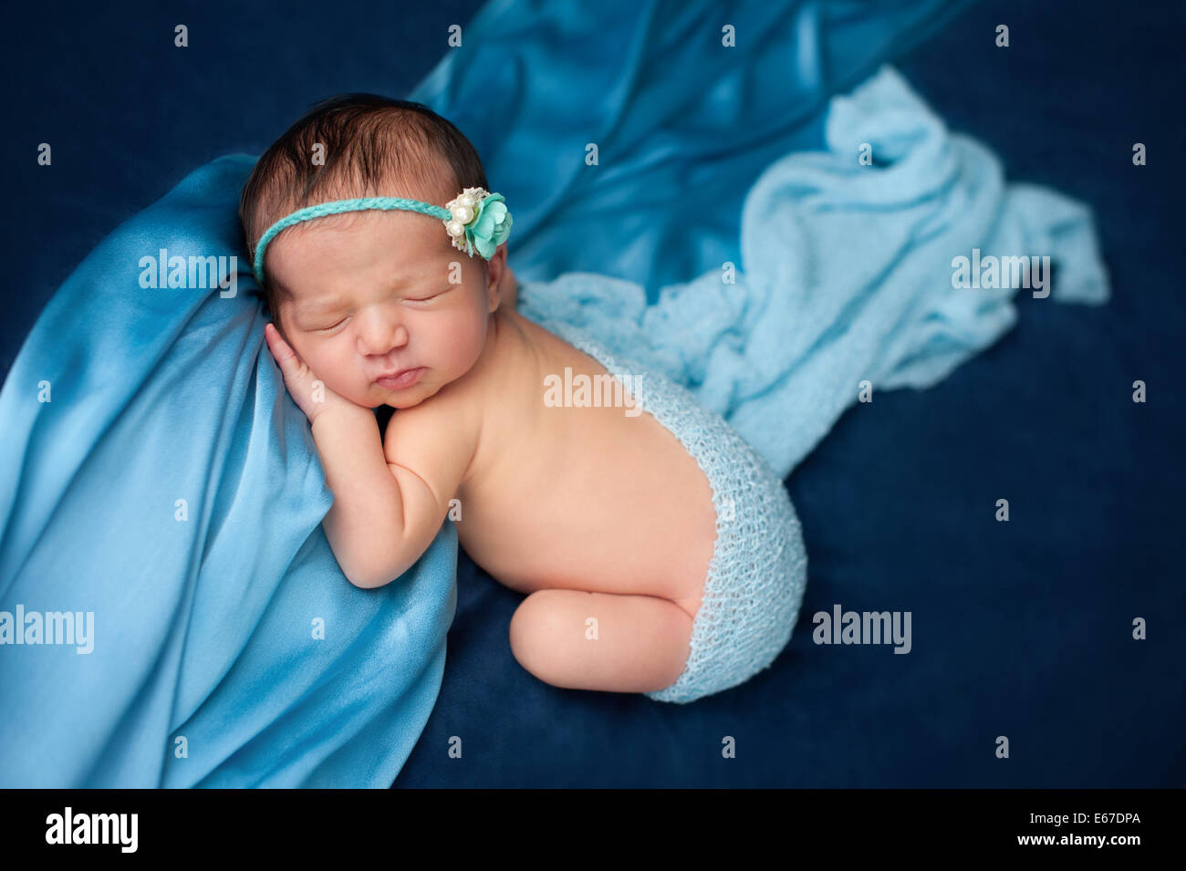 Six day old newborn baby girl wearing a paper rose and pearl headband ...