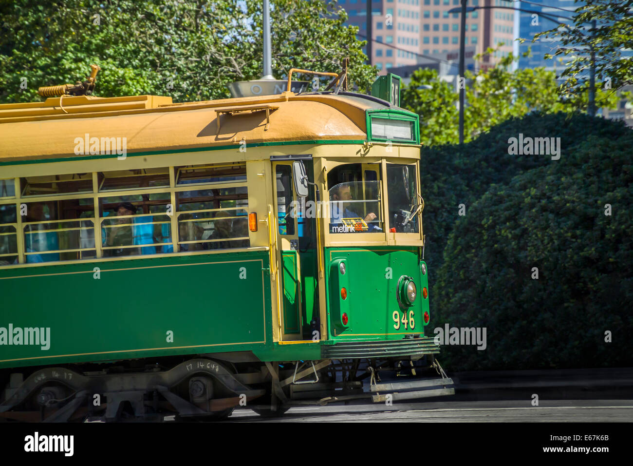 Green traditional iconic Melbourne tram travelling up a hill towards ...