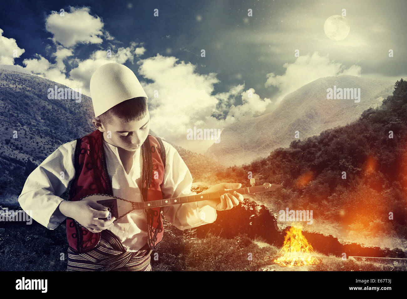 albanian musician kid playing string instrument outside in camp fire ...