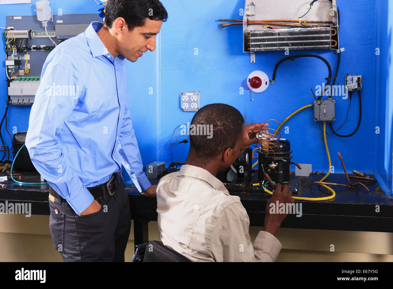 Students examining condenser coil on refrigeration unit in HVAC ...