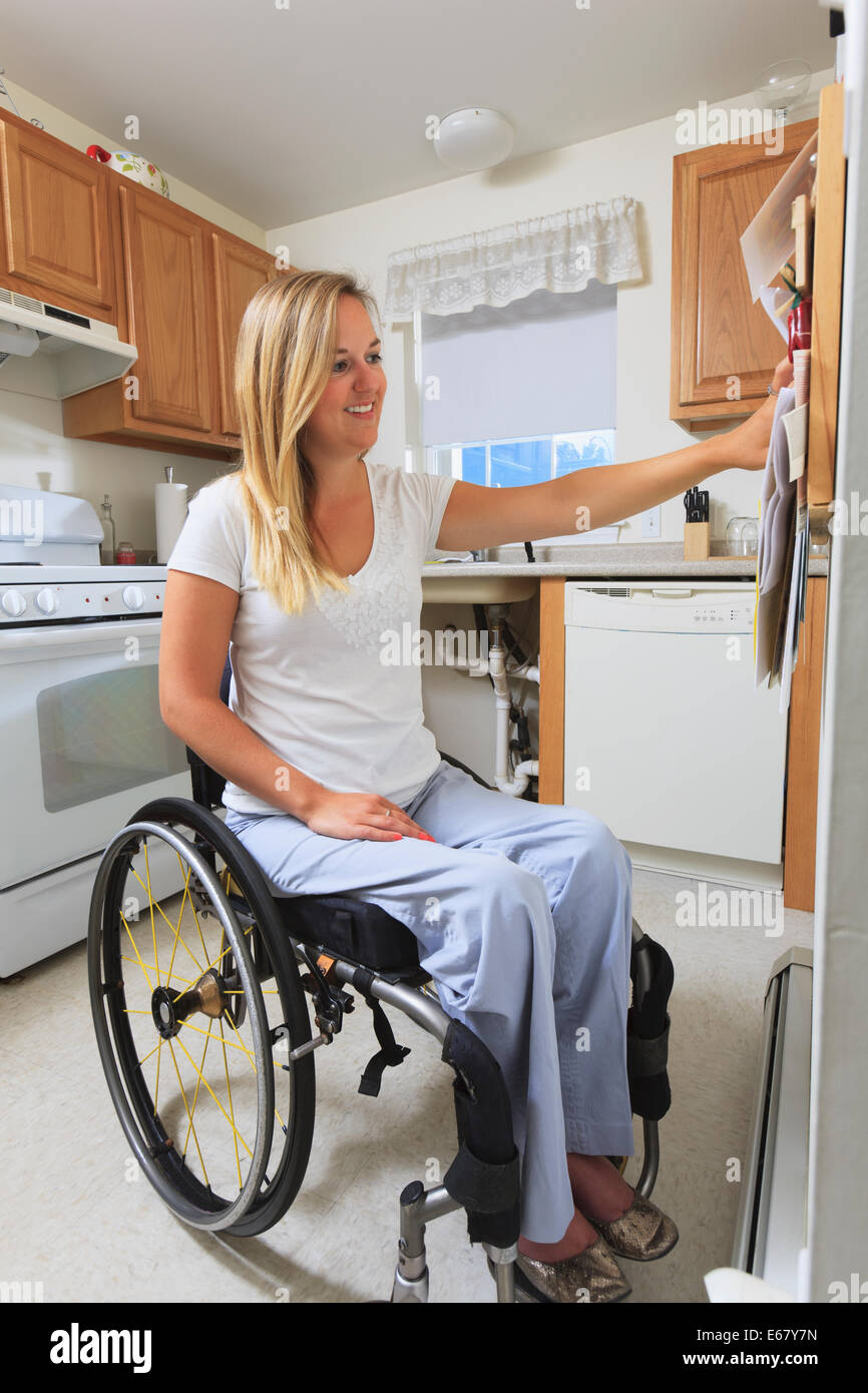 Woman with spinal cord injury in her accessible kitchen looking at ...