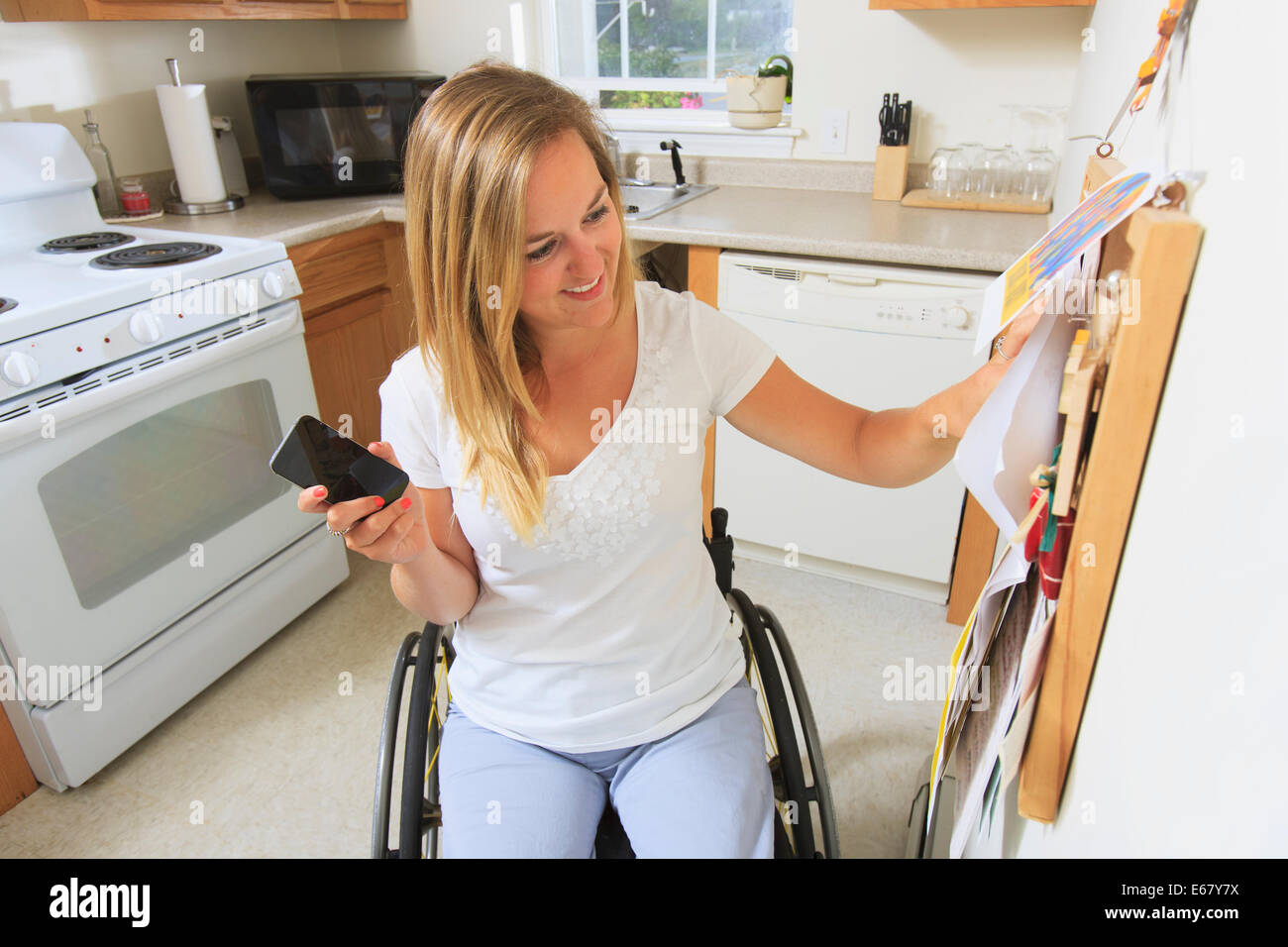 Woman with spinal cord injury in her accessible kitchen looking at ...