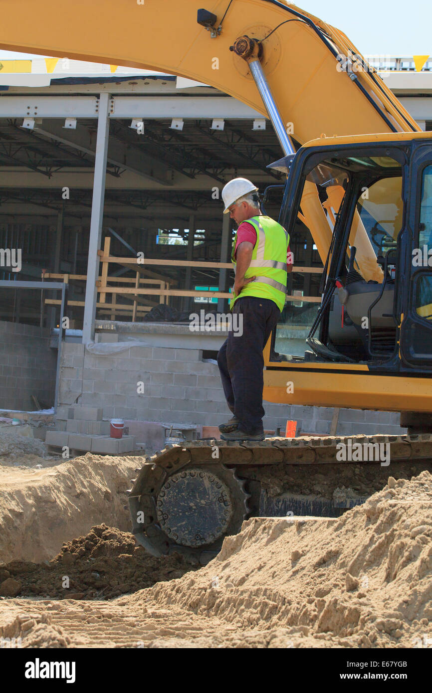 Construction engineer standing on the excavator inspecting the trench ...