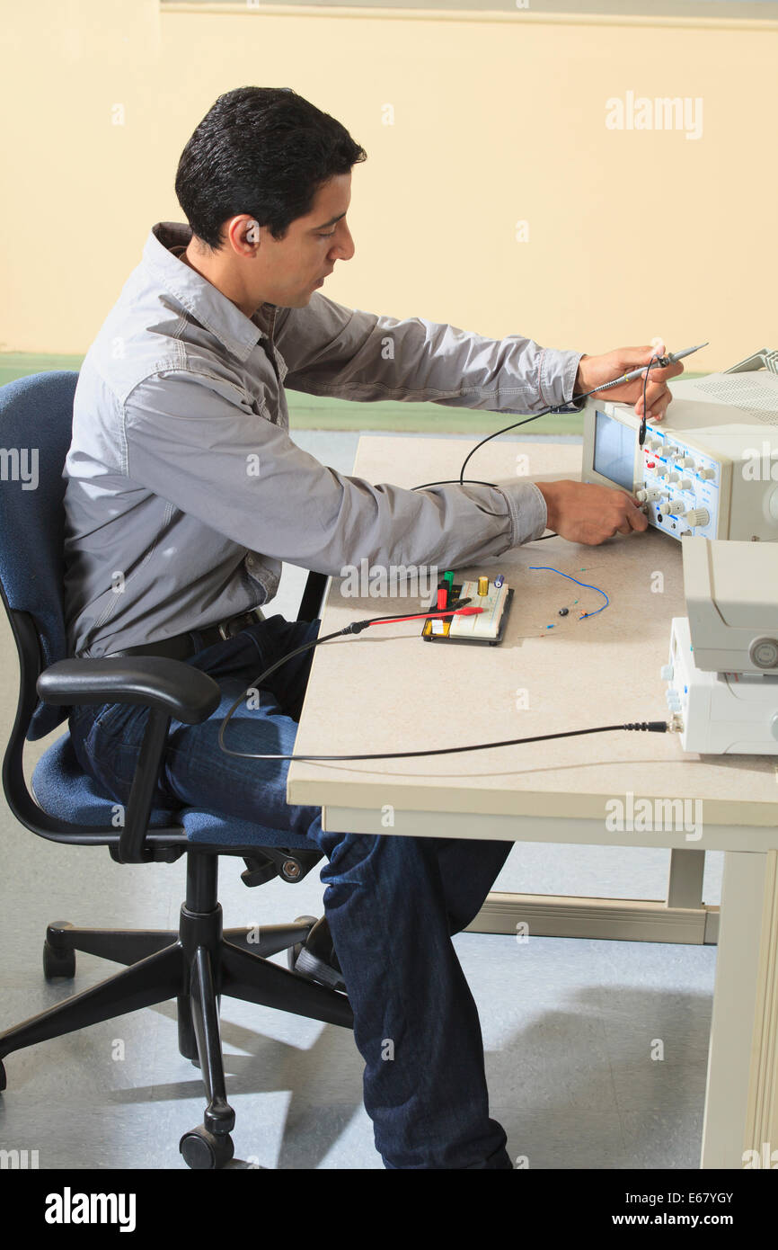 Engineering student adjusting oscilloscope to measure prototyping ...