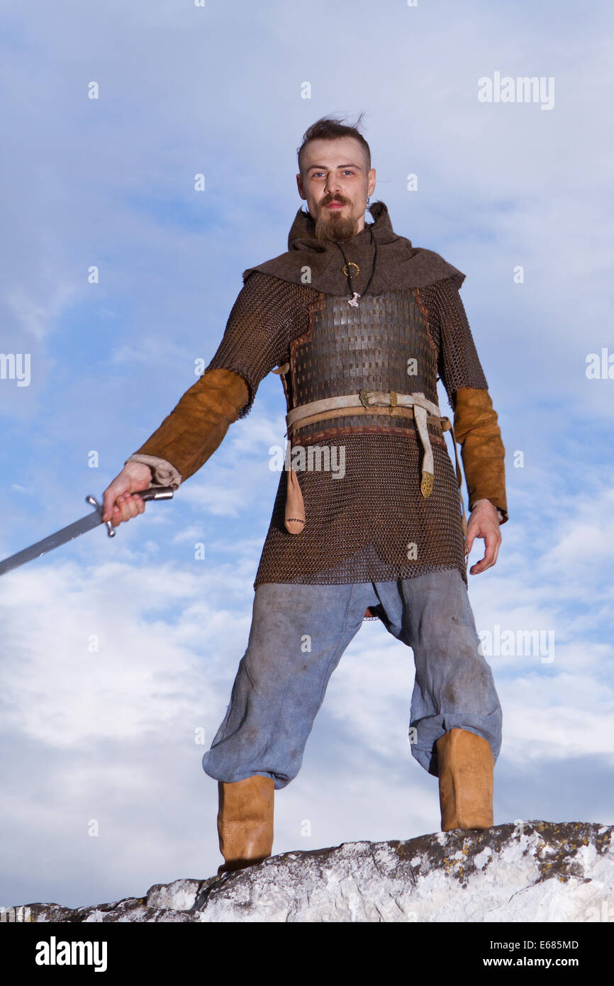 Knight on a rock with a sword against blue cloudy sky Stock Photo - Alamy