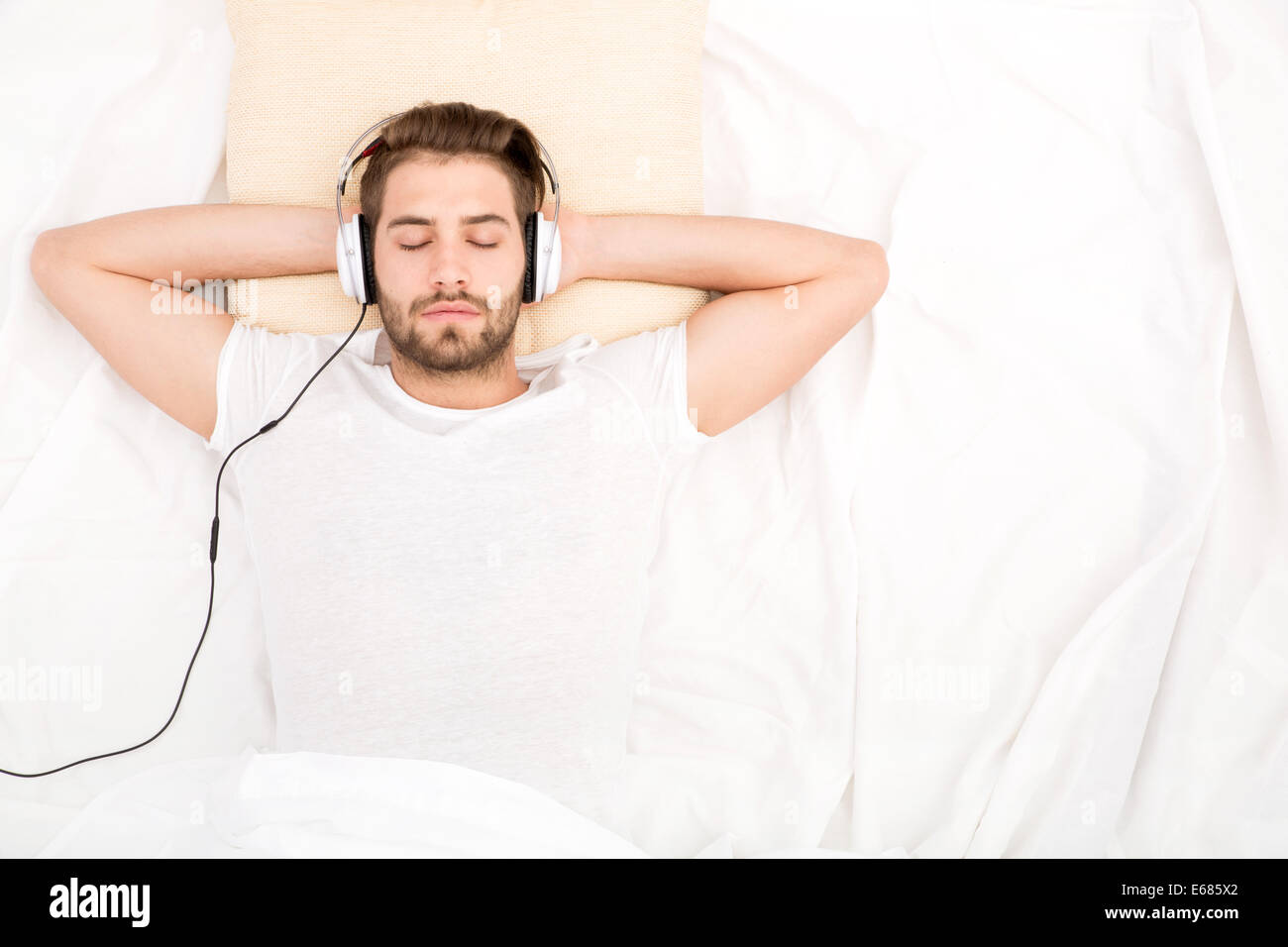 Portrait of a handsome man from above with headphones in bed Stock ...