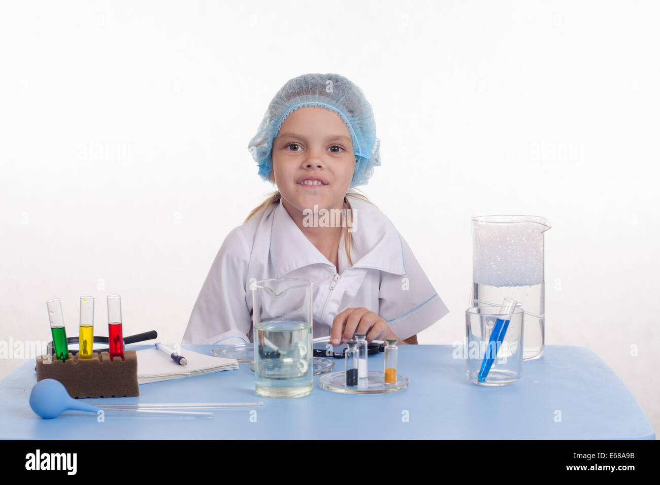 Chemist girl sitting at the table with the reagents in chemistry class ...