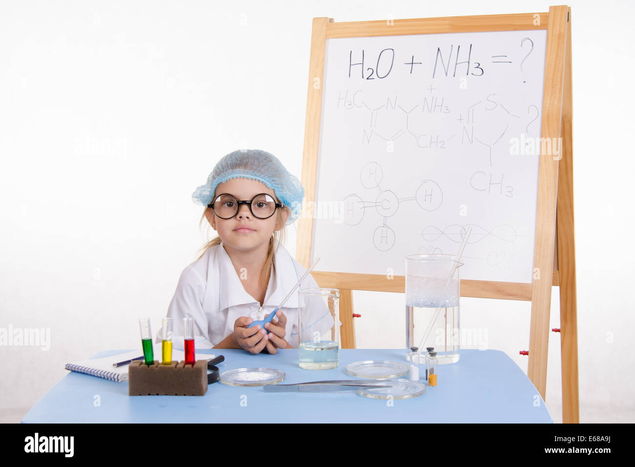 Chemist girl sitting at the table with the reagents in chemistry class ...
